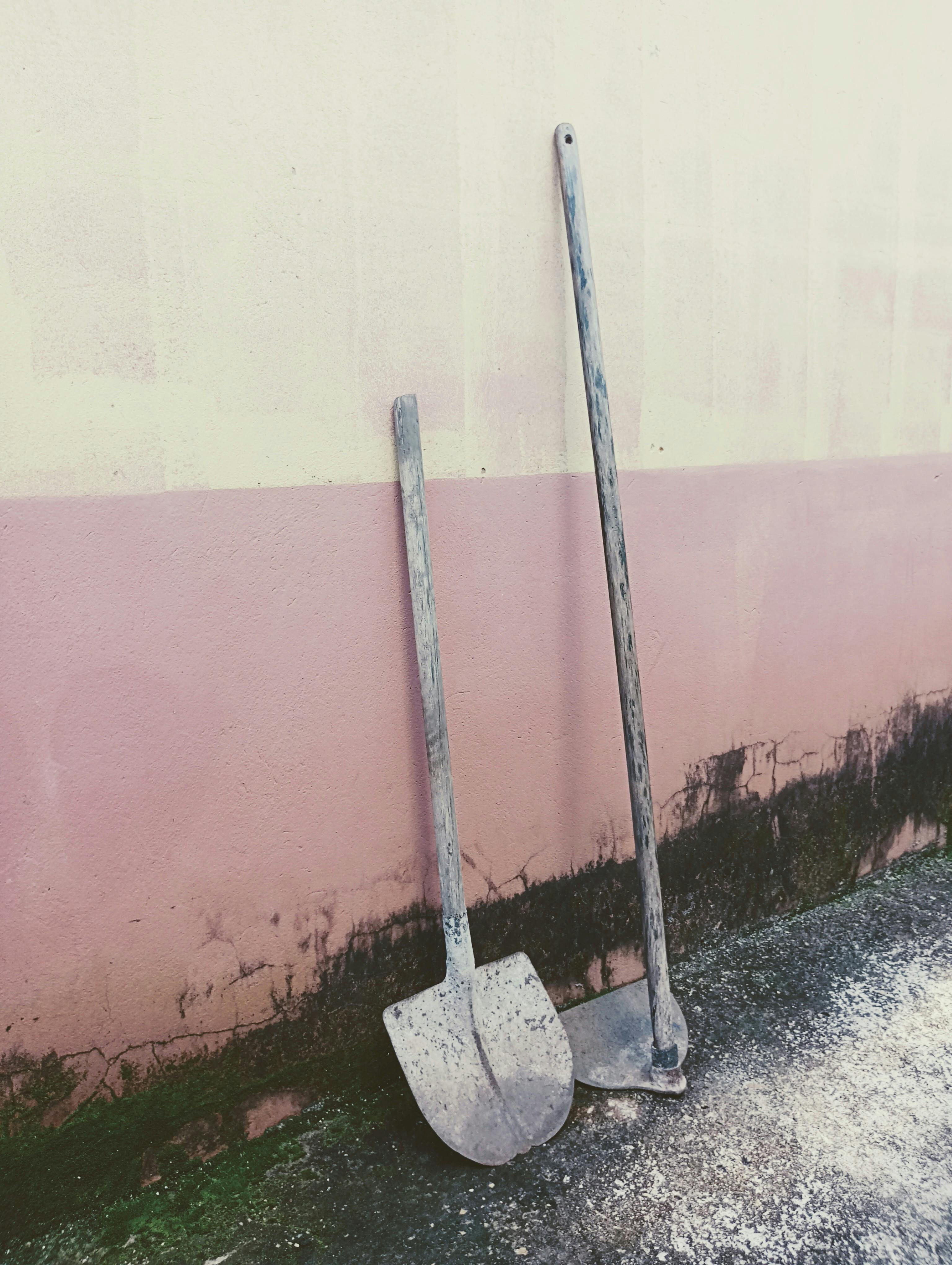 Old Shovel and Hoe Against Rustic Wall · Free Stock Photo
