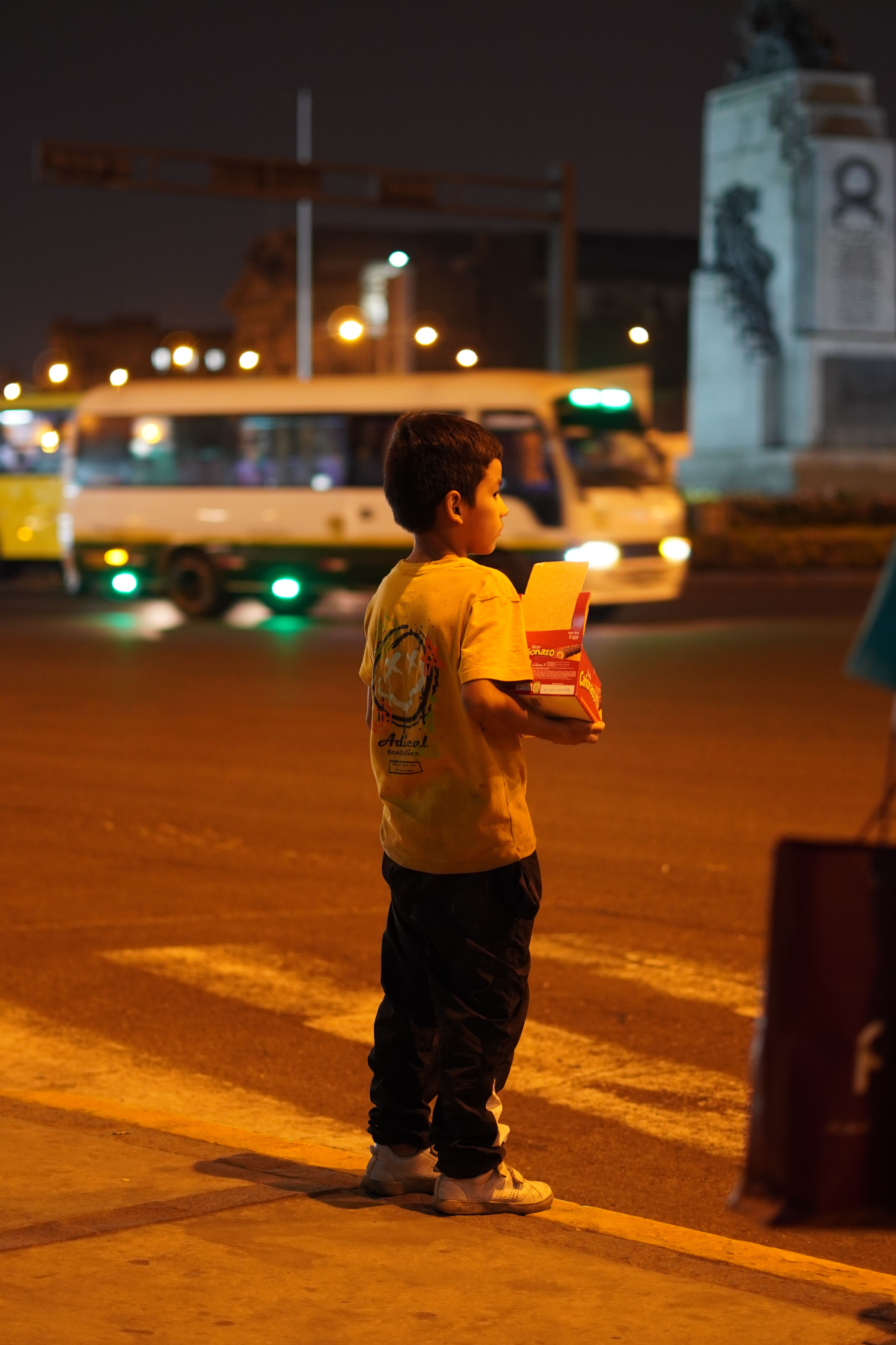 Child on Lima Street at Night Holding Items · Free Stock Photo