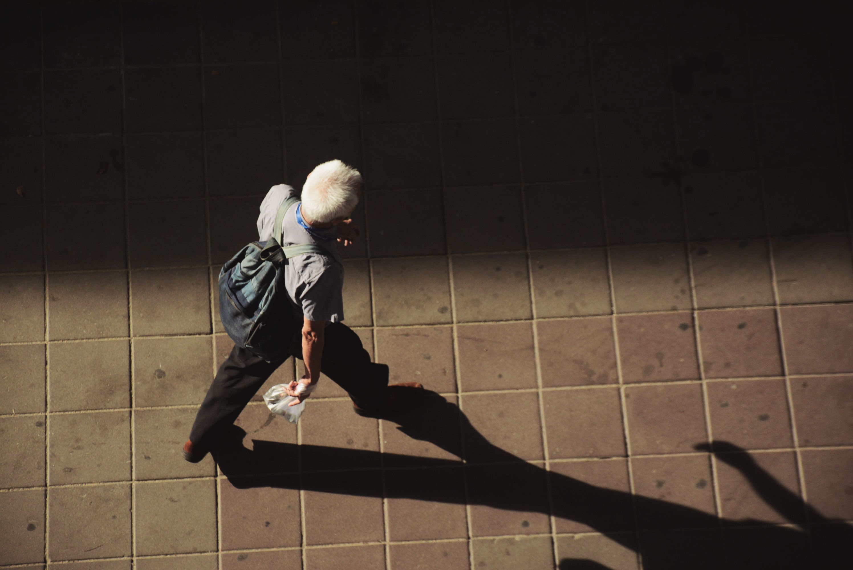 Senior Man Walking with Long Shadow on Bangkok Street · Free Stock Photo