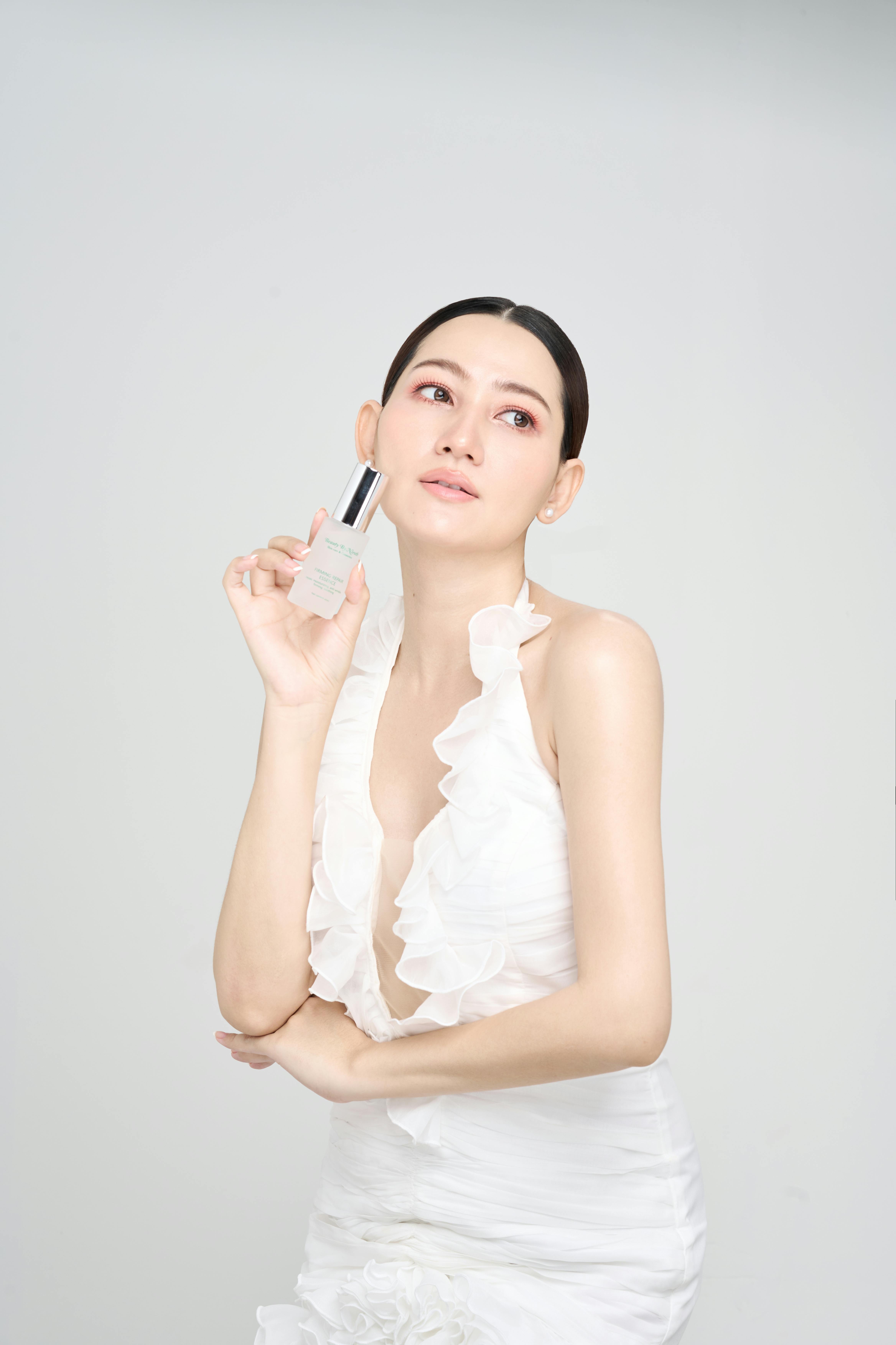 Elegant Skincare Product Model in White Dress · Free Stock Photo