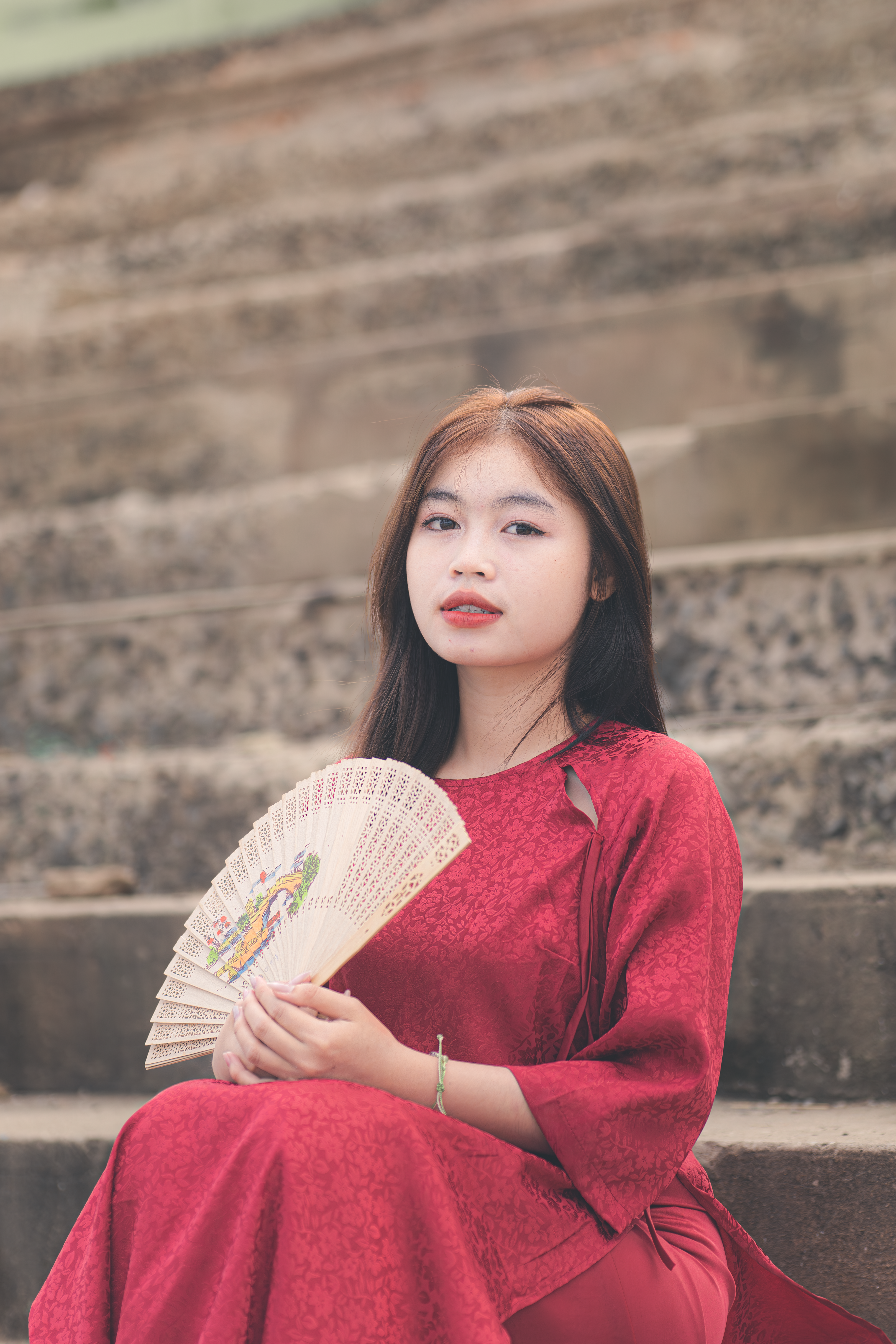 Young Woman in Red Holding Traditional Fan on Steps · Free Stock Photo