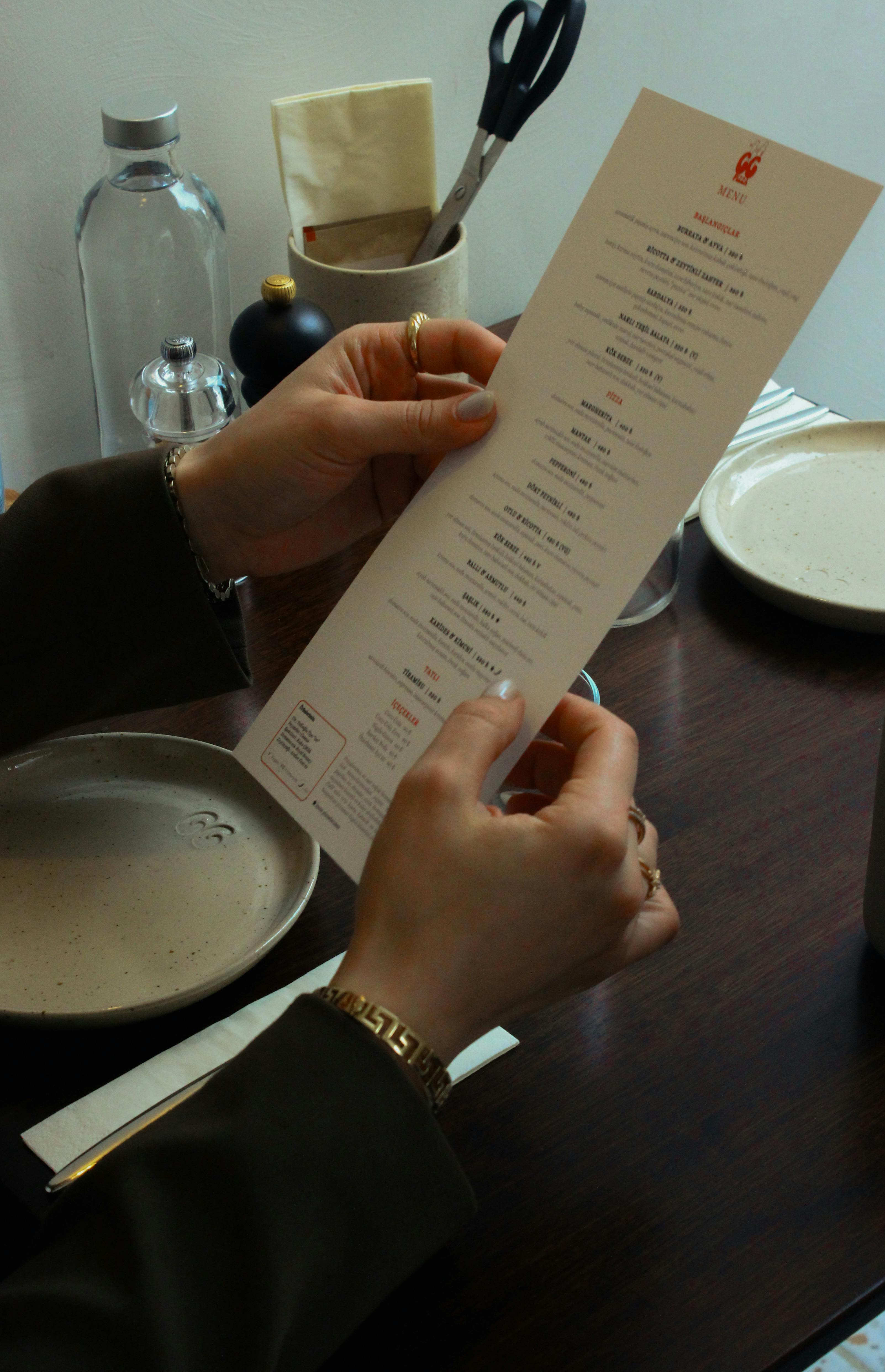 Hands Holding Menu at Restaurant Table · Free Stock Photo