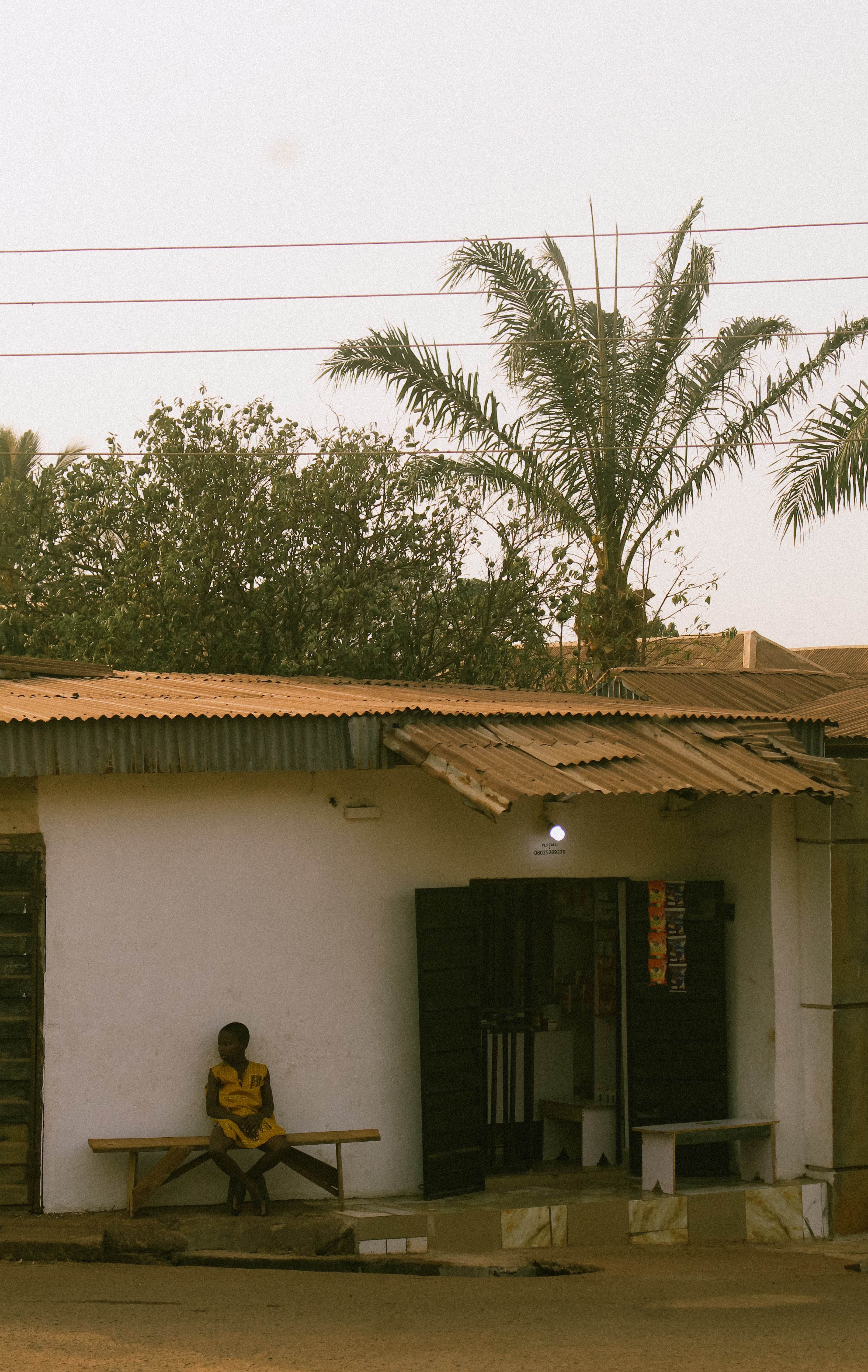 Solitary Child Sitting Near Street Shop in Enugu · Free Stock Photo