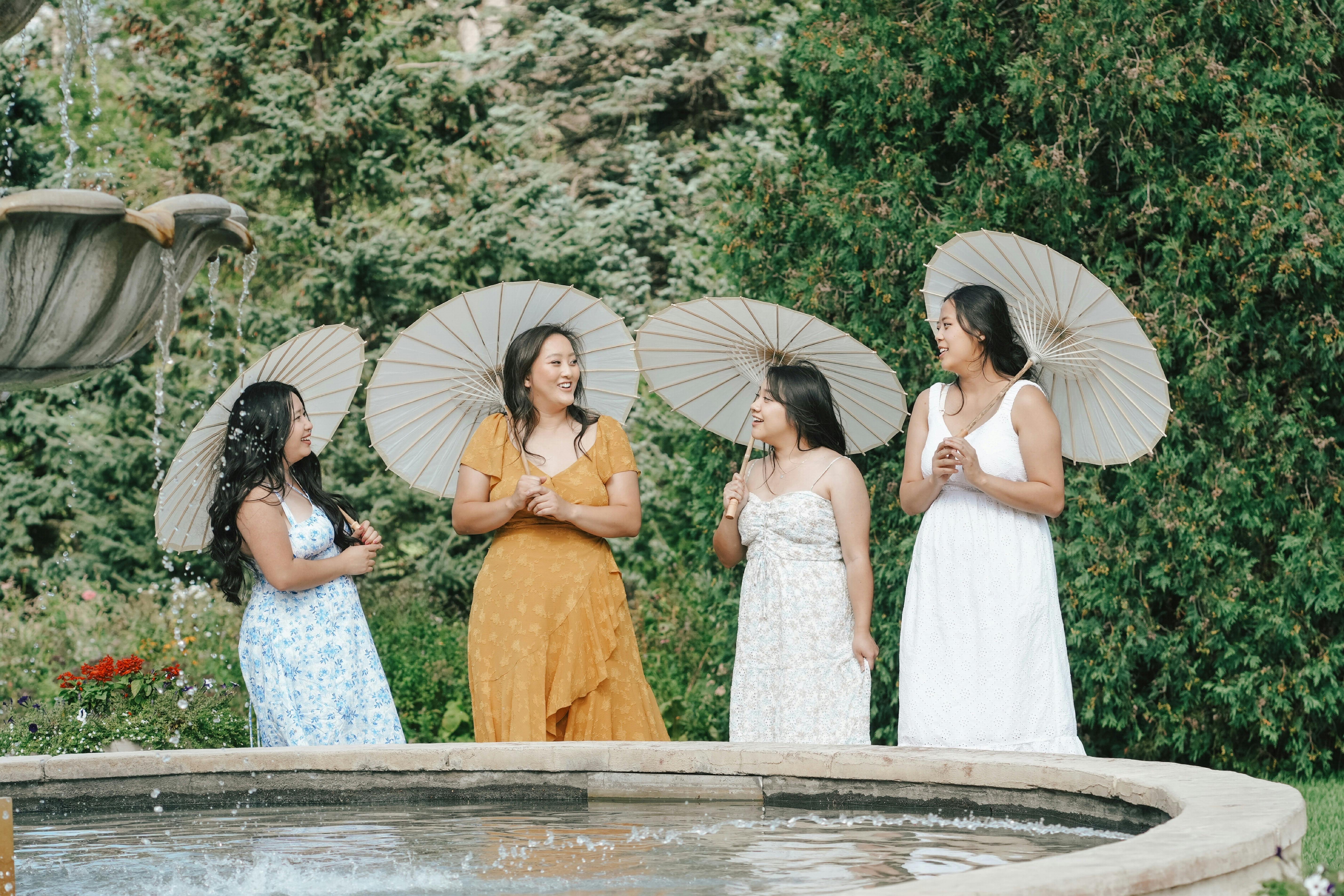 Four Women Enjoying a Garden with Parasol Decor · Free Stock Photo
