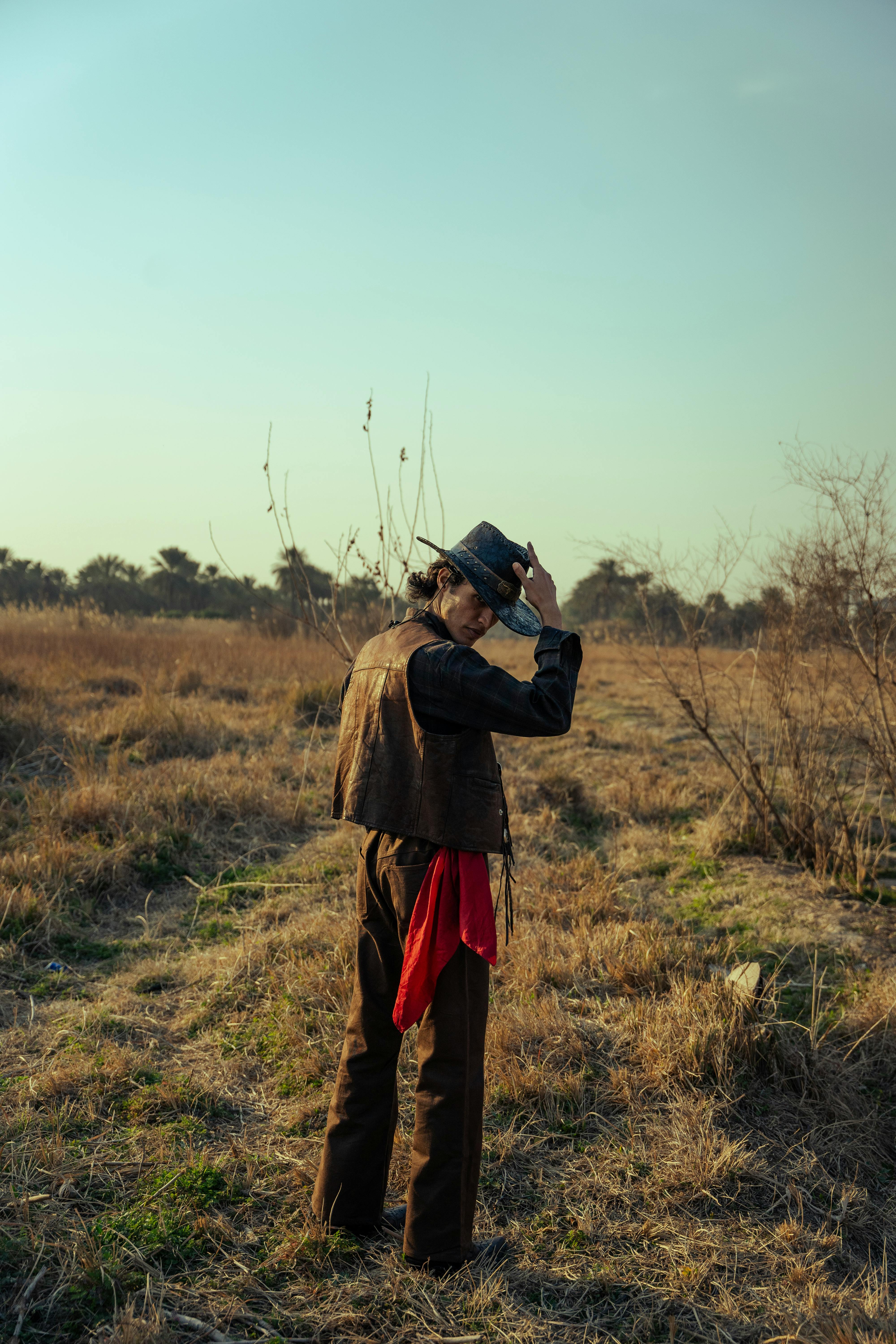 Cowboy in Autumn Field Adjusting Hat · Free Stock Photo