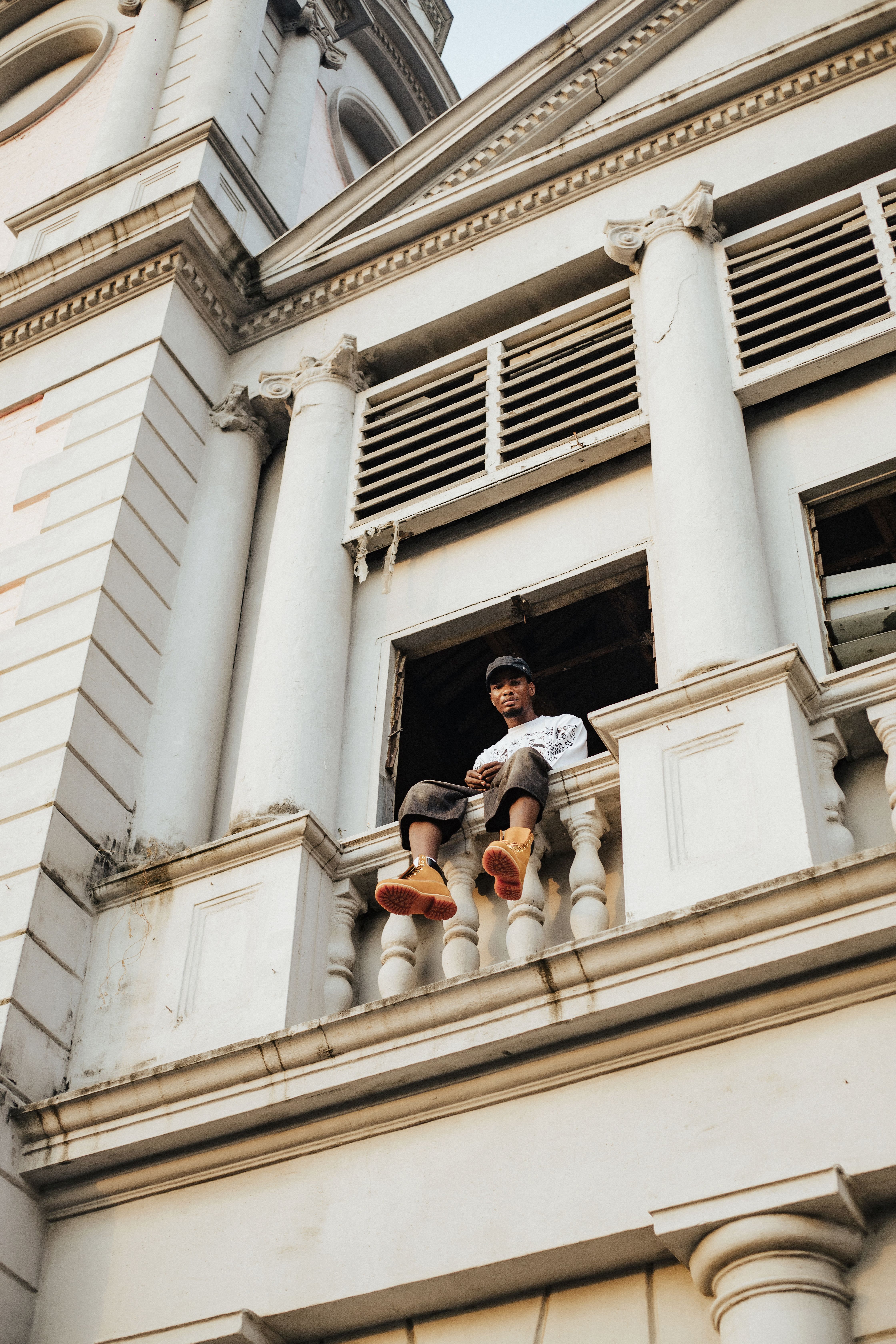 Young Man Sitting on an Urban Building Ledged · Free Stock Photo