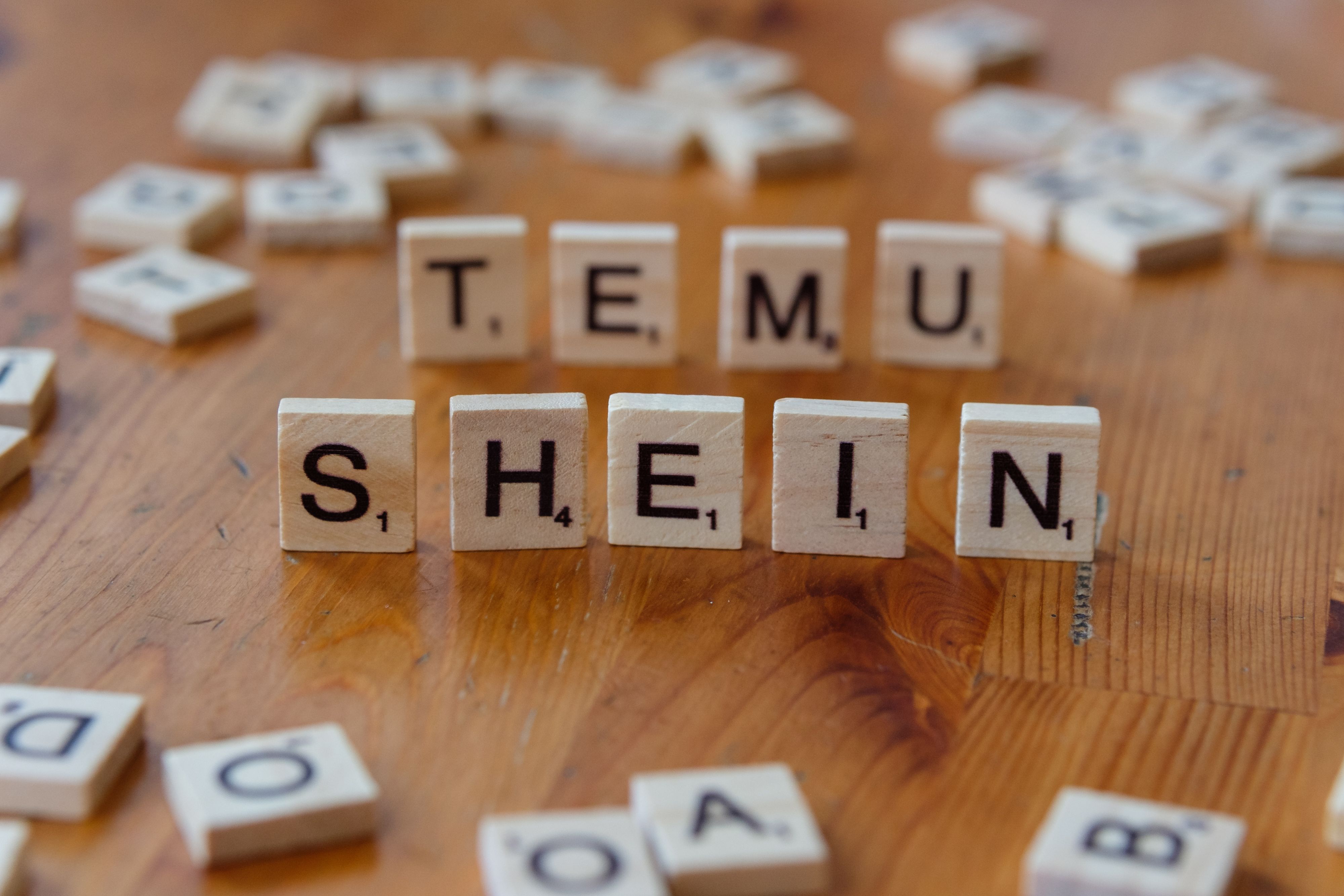 Scrabble Tiles Spelling 'TEMU SHEIN' on Wooden Table · Free Stock Photo