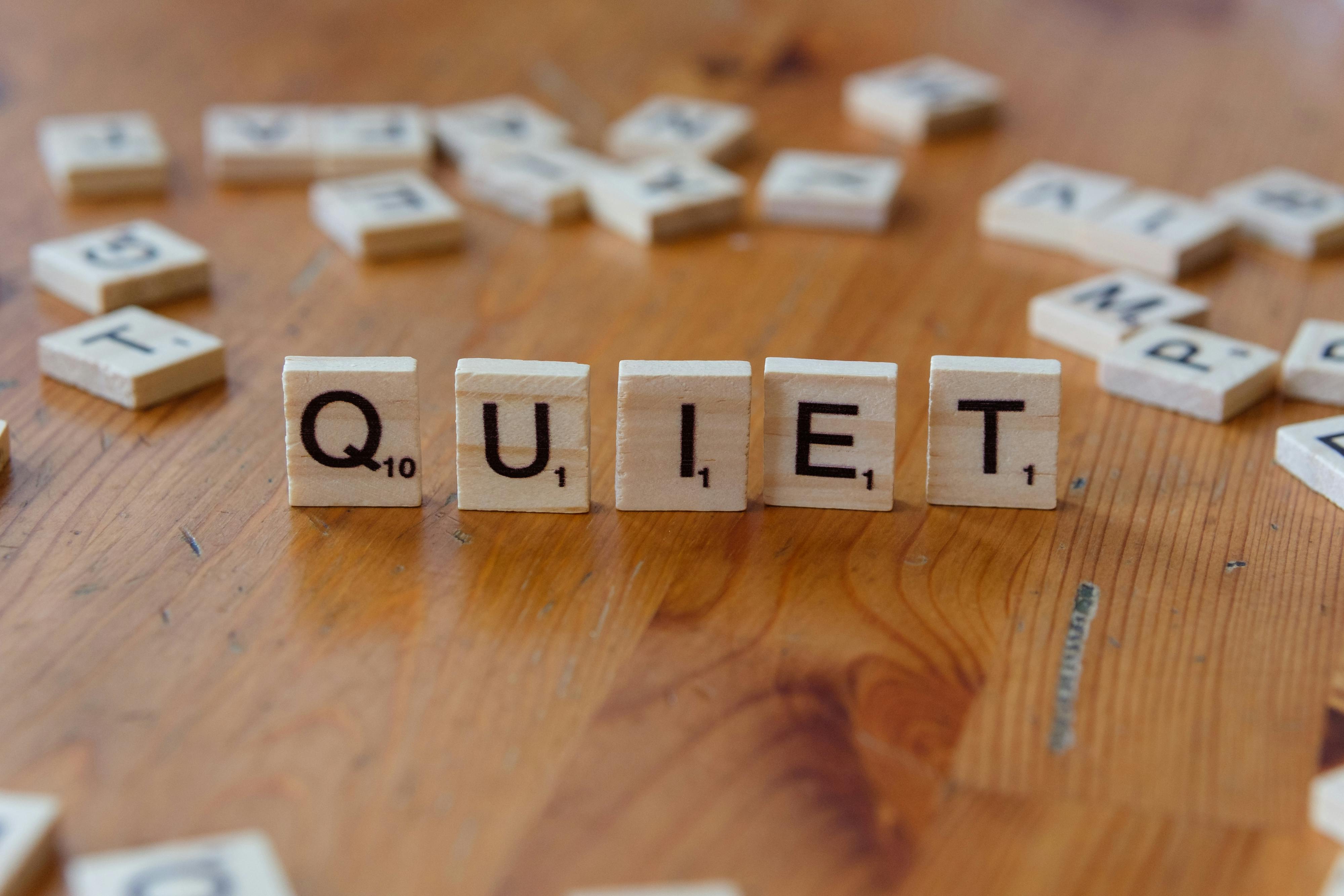 Scrabble Letters Spelling 'Quiet' on Wooden Table · Free Stock Photo