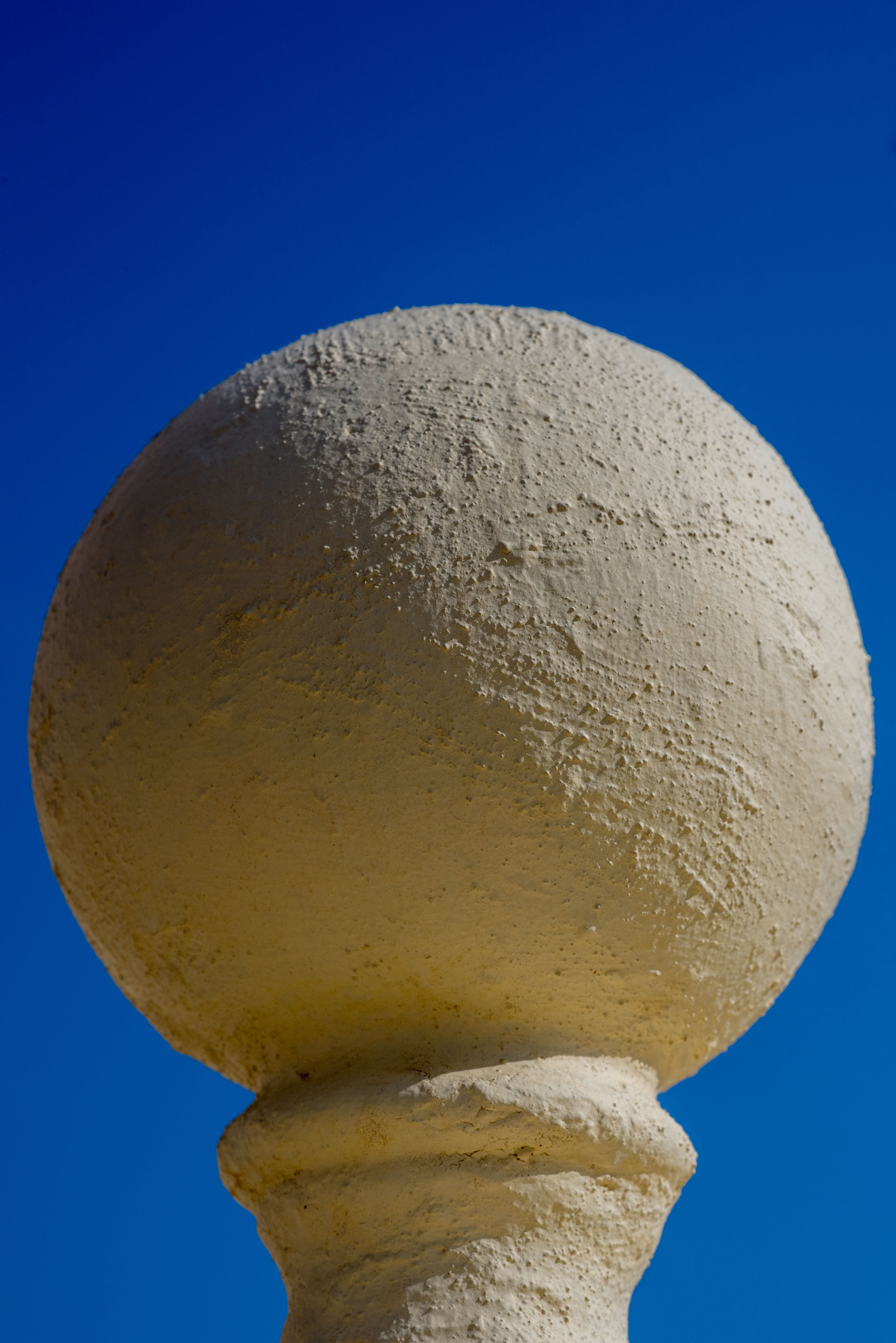 Textured Stone Sphere Against Clear Blue Sky · Free Stock Photo