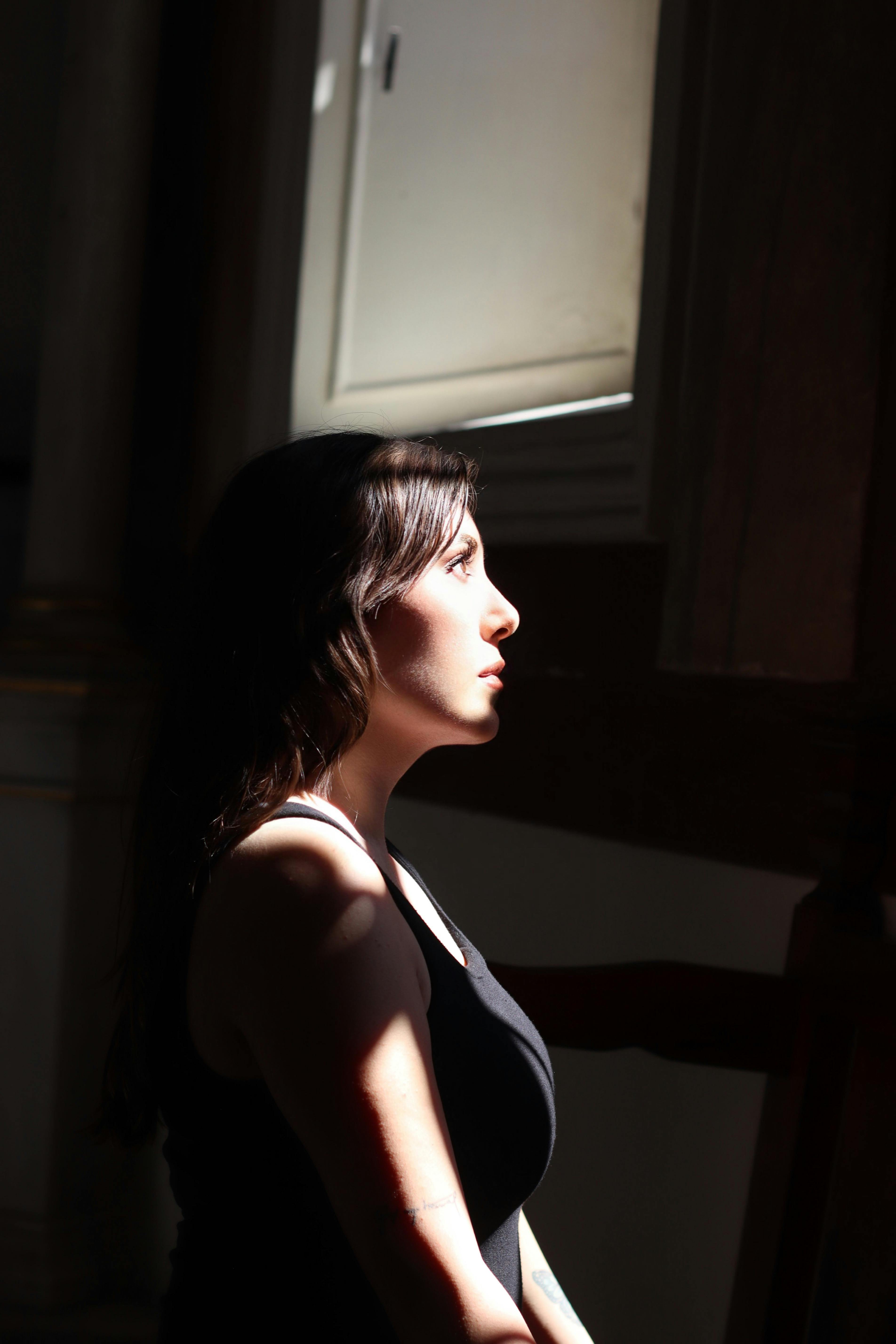 Contemplative Woman in Dramatic Window Light · Free Stock Photo