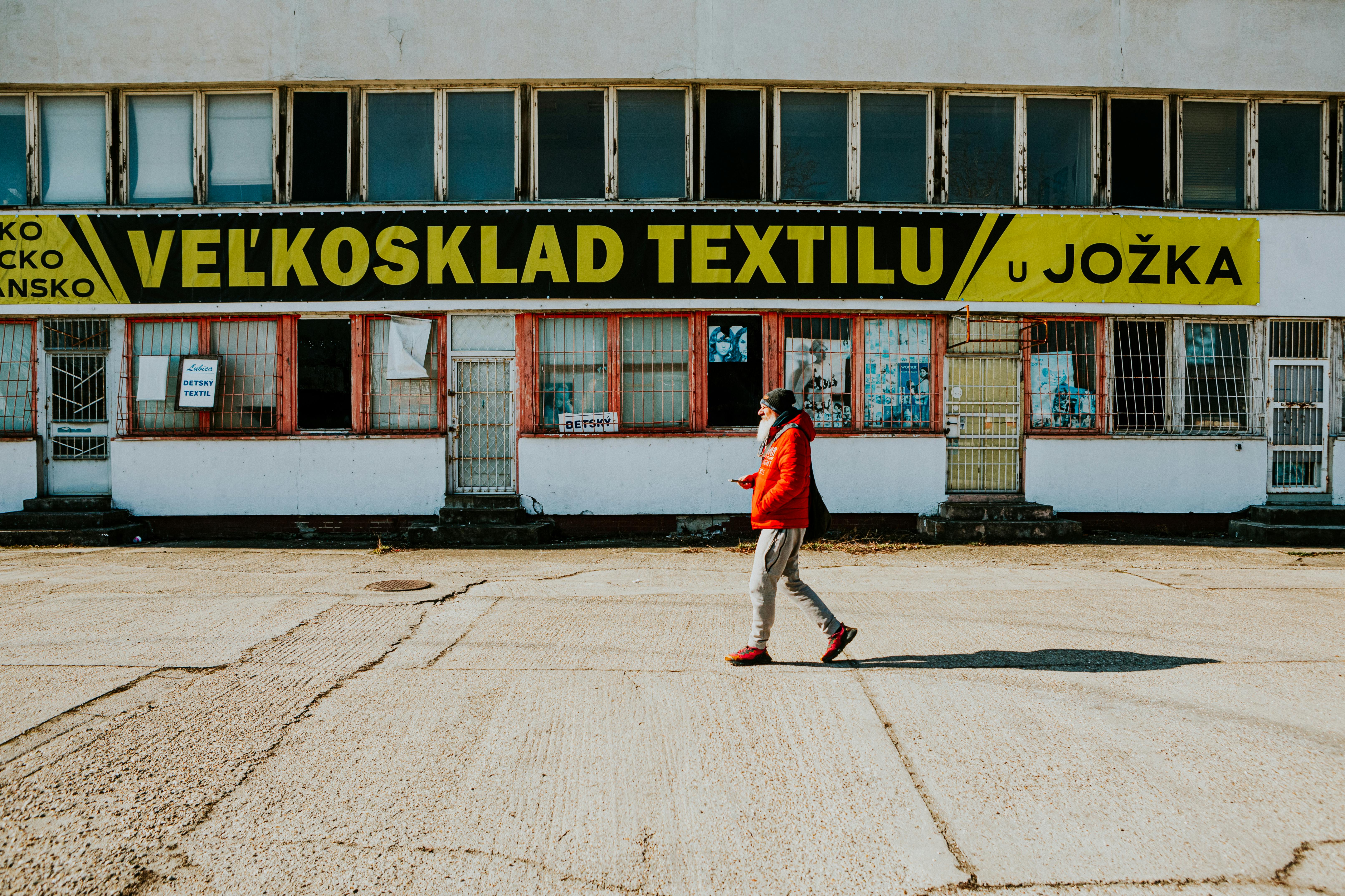 Man Walking Past Textile Storefront in Slovakia · Free Stock Photo