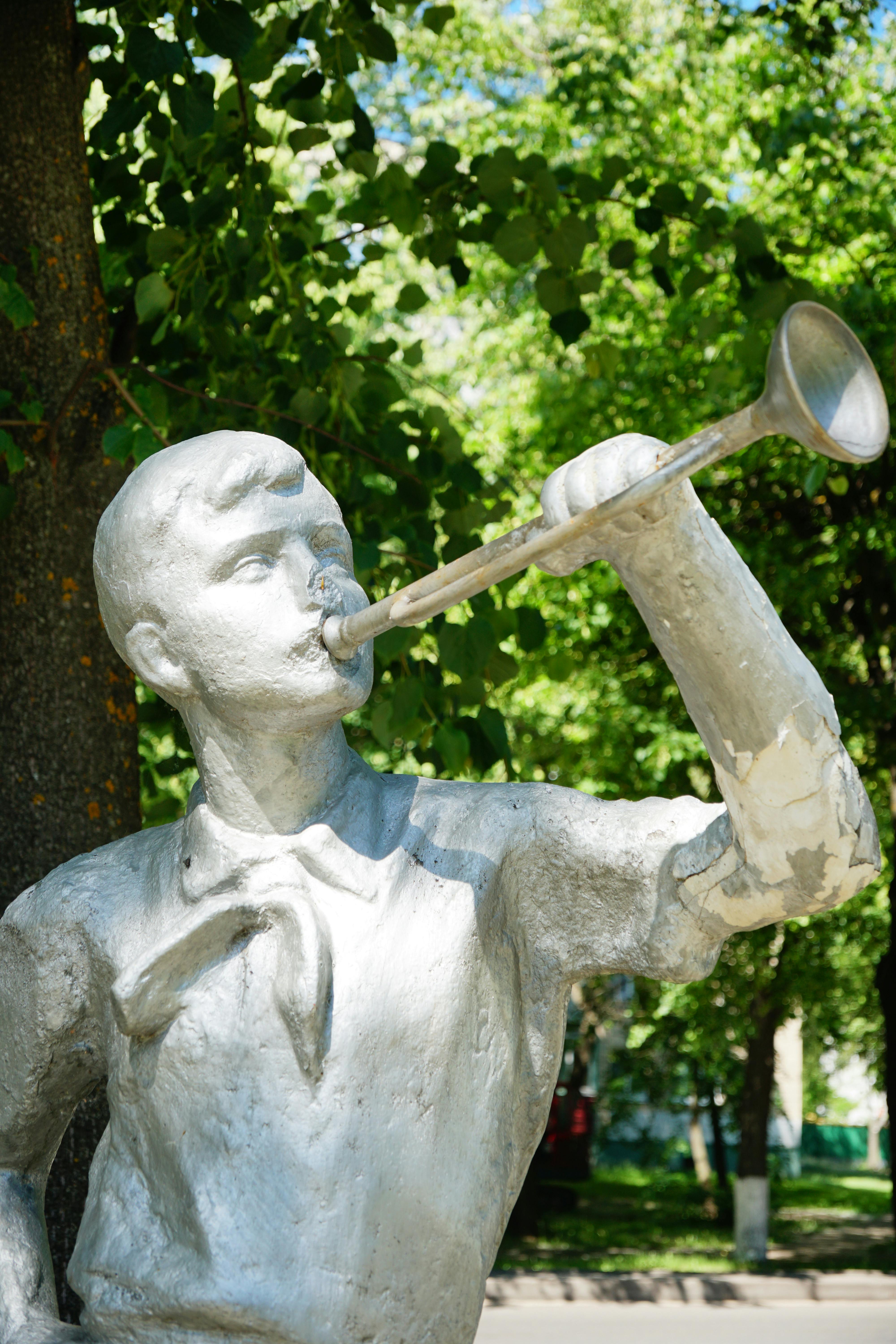 Statue of Boy Playing Trumpet in Park Setting · Free Stock Photo
