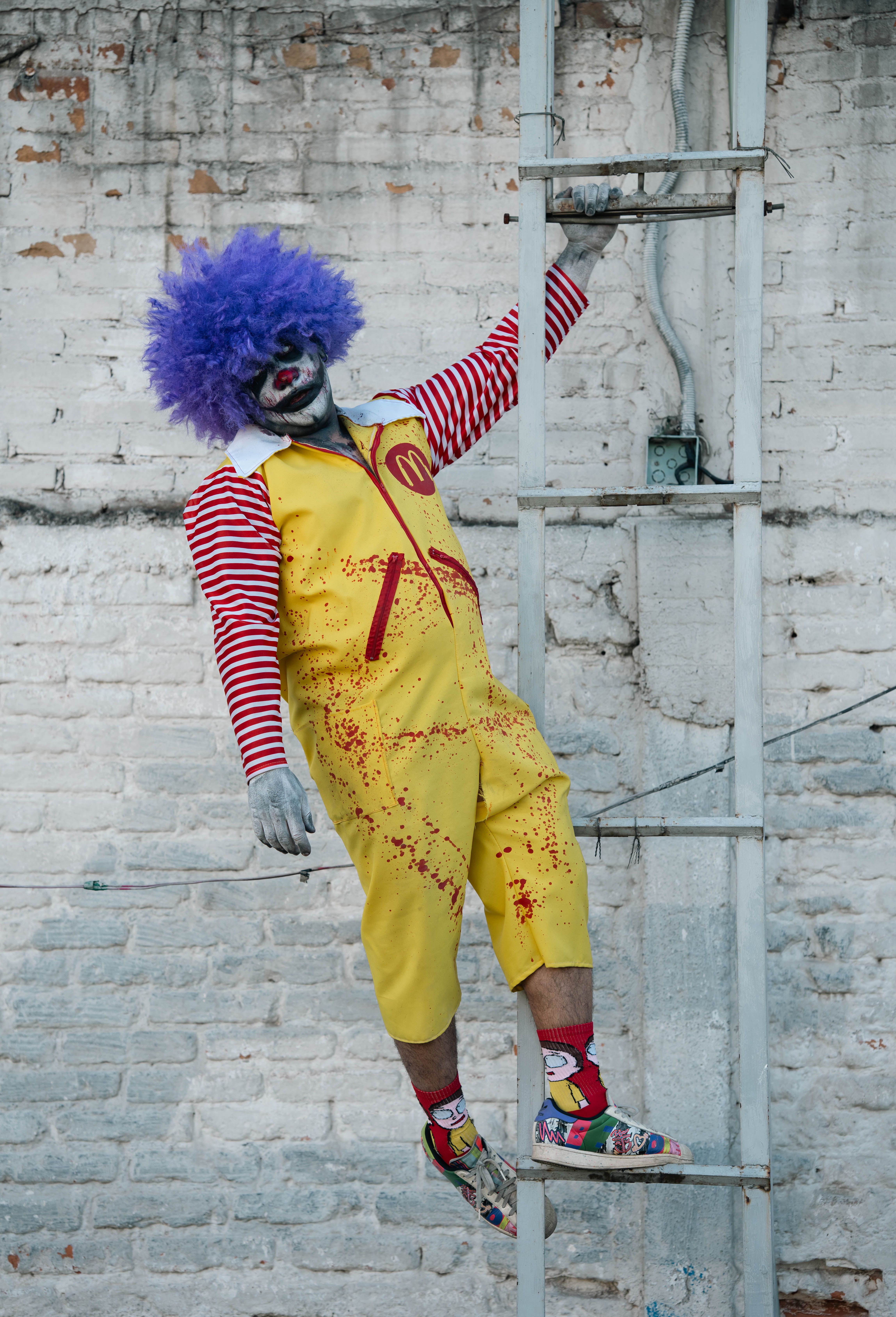 Colorful Clown Climbing Ladder in Urban Setting · Free Stock Photo