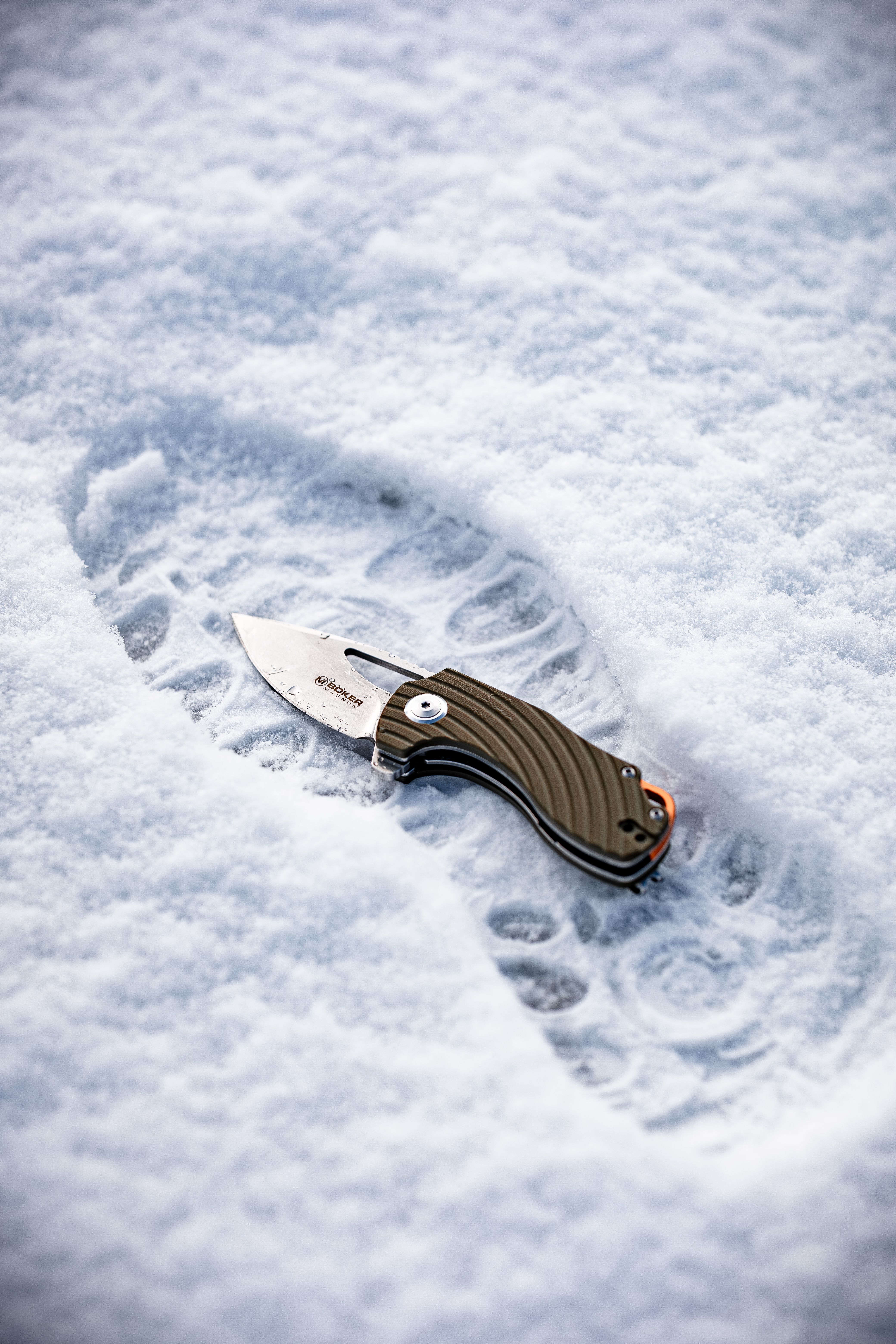 Folding knife placed within a snowy footprint · Free Stock Photo