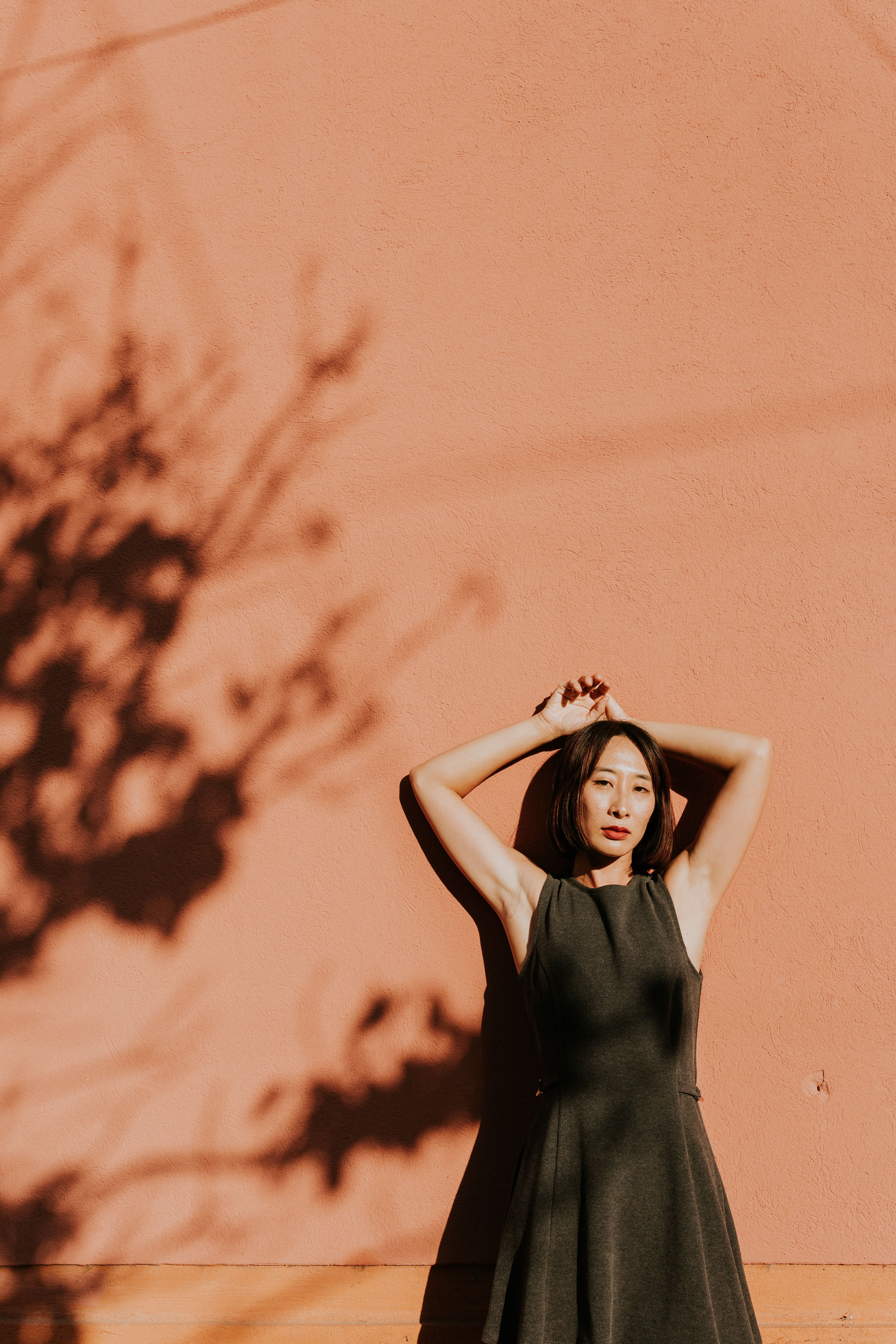 Woman Standing Behind Wall With Shadow of Tree · Free Stock Photo