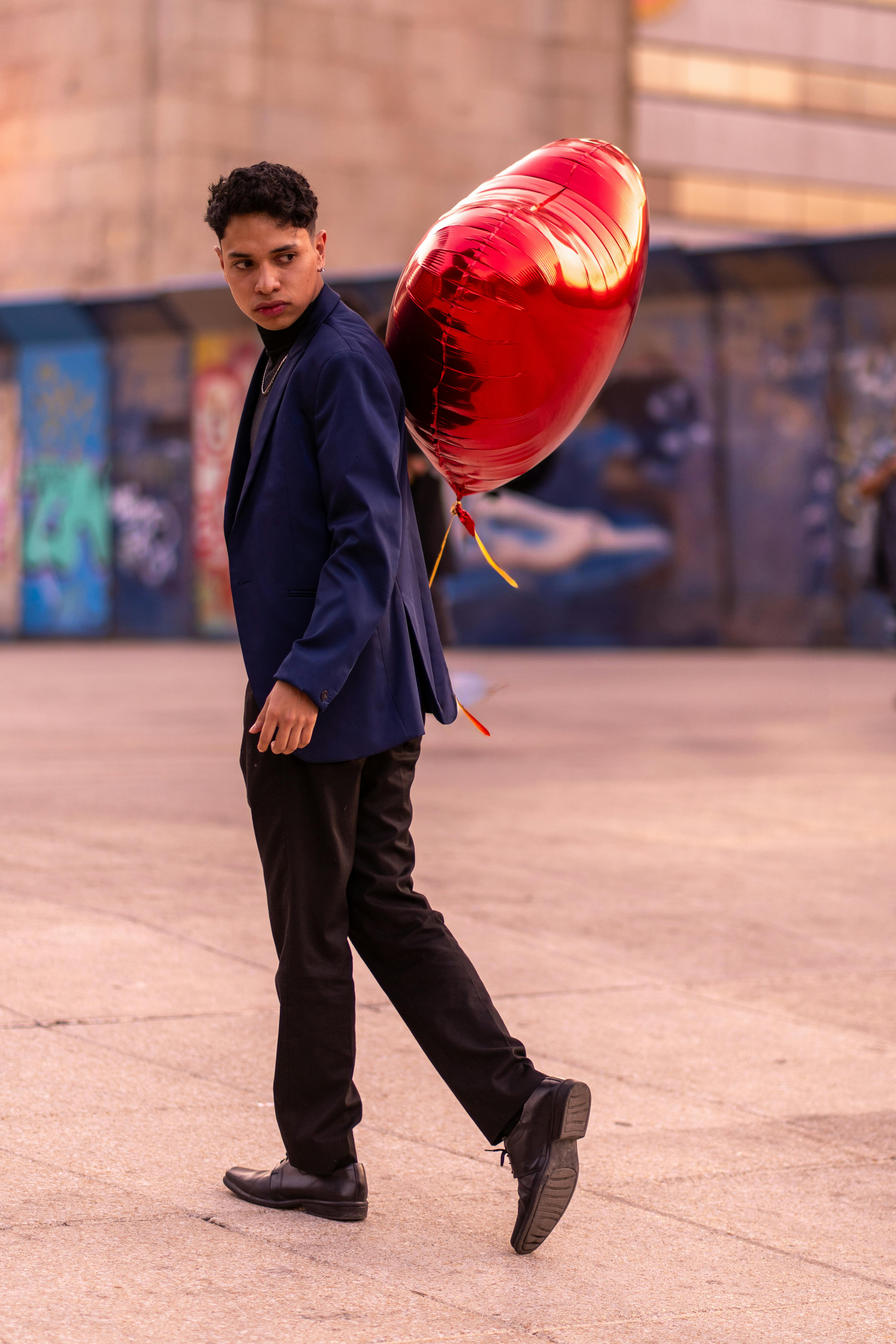 Stylish young man walking with heart balloon outdoors · Free Stock Photo