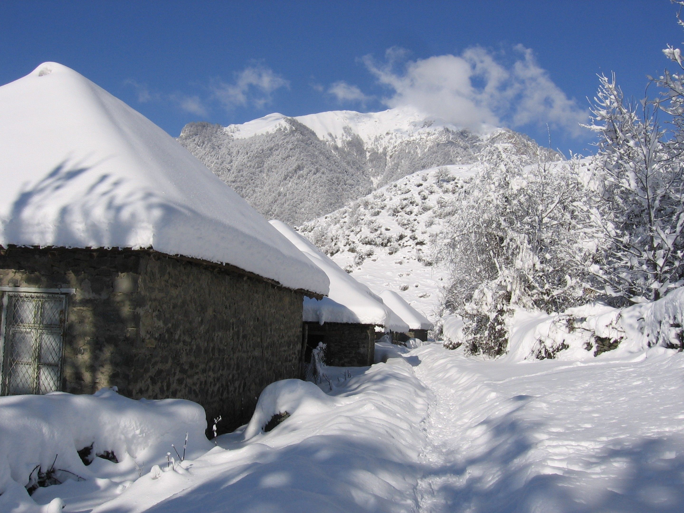 Snow-Covered Stone Huts in Mountain Village · Free Stock Photo