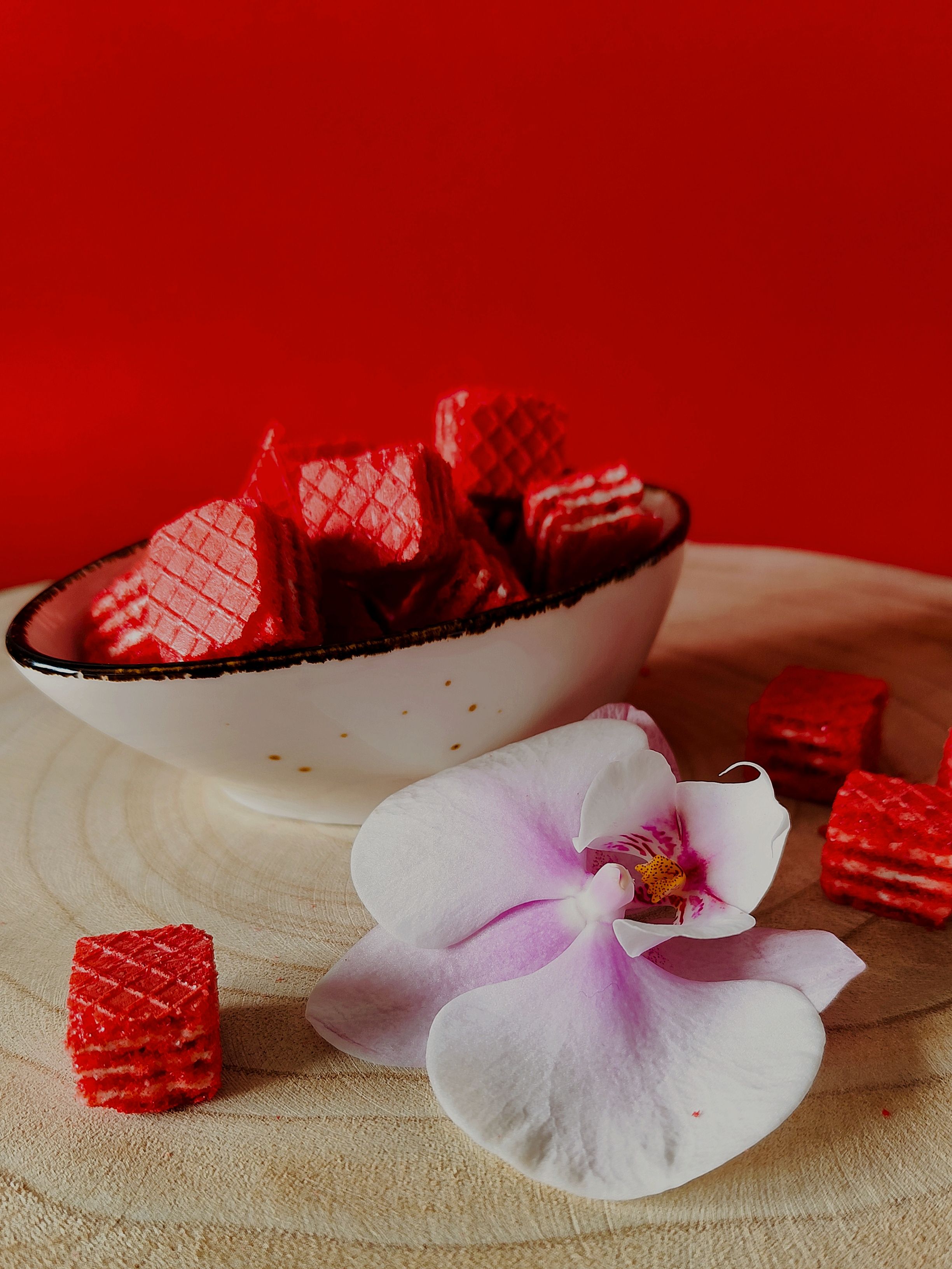 Red Wafer Biscuits with Orchid on Wooden Surface · Free Stock Photo