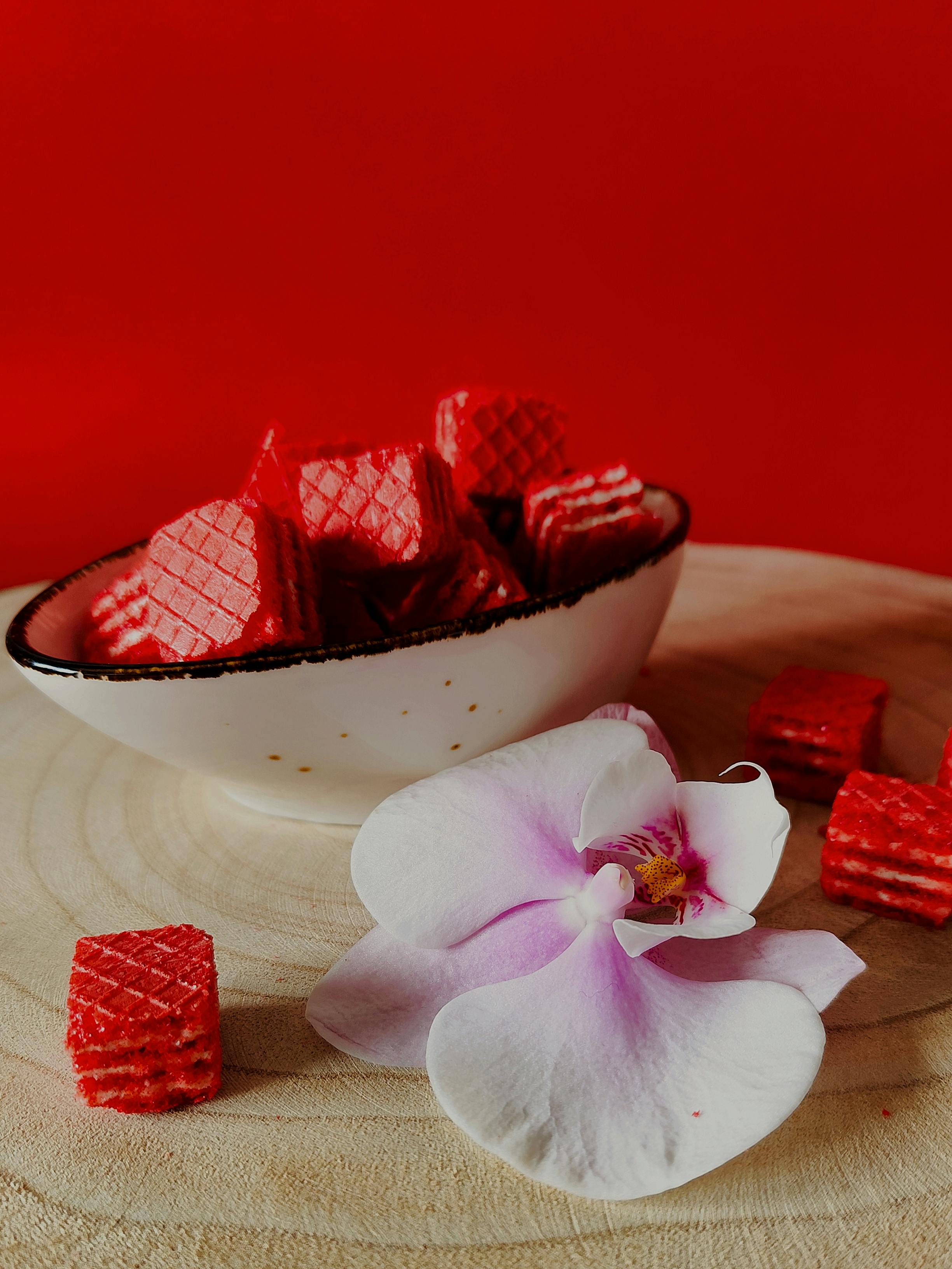 Red Wafer Biscuits with Orchid on Wooden Surface · Free Stock Photo
