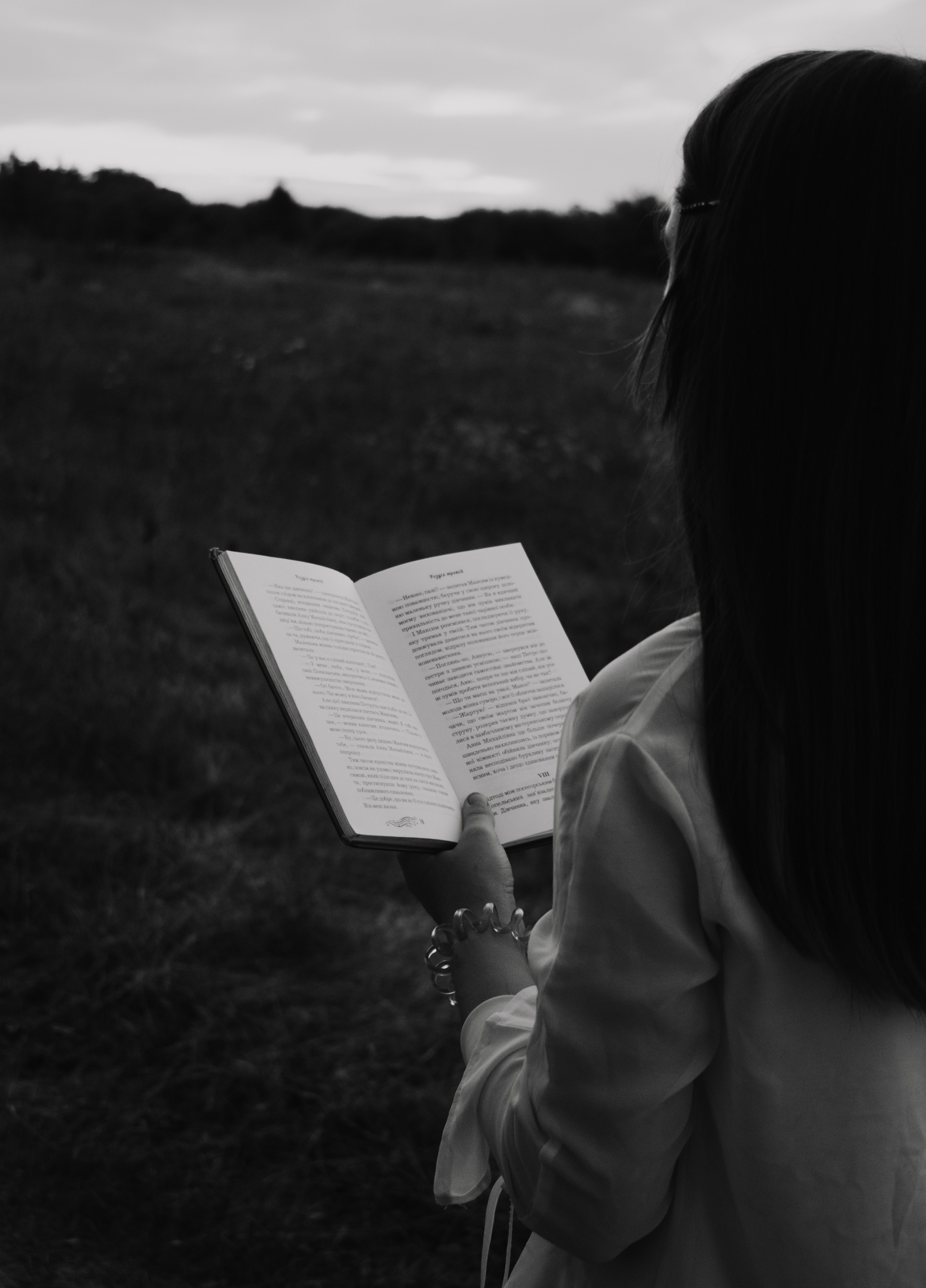 Girl Reading Book in Peaceful Meadow at Dusk · Free Stock Photo