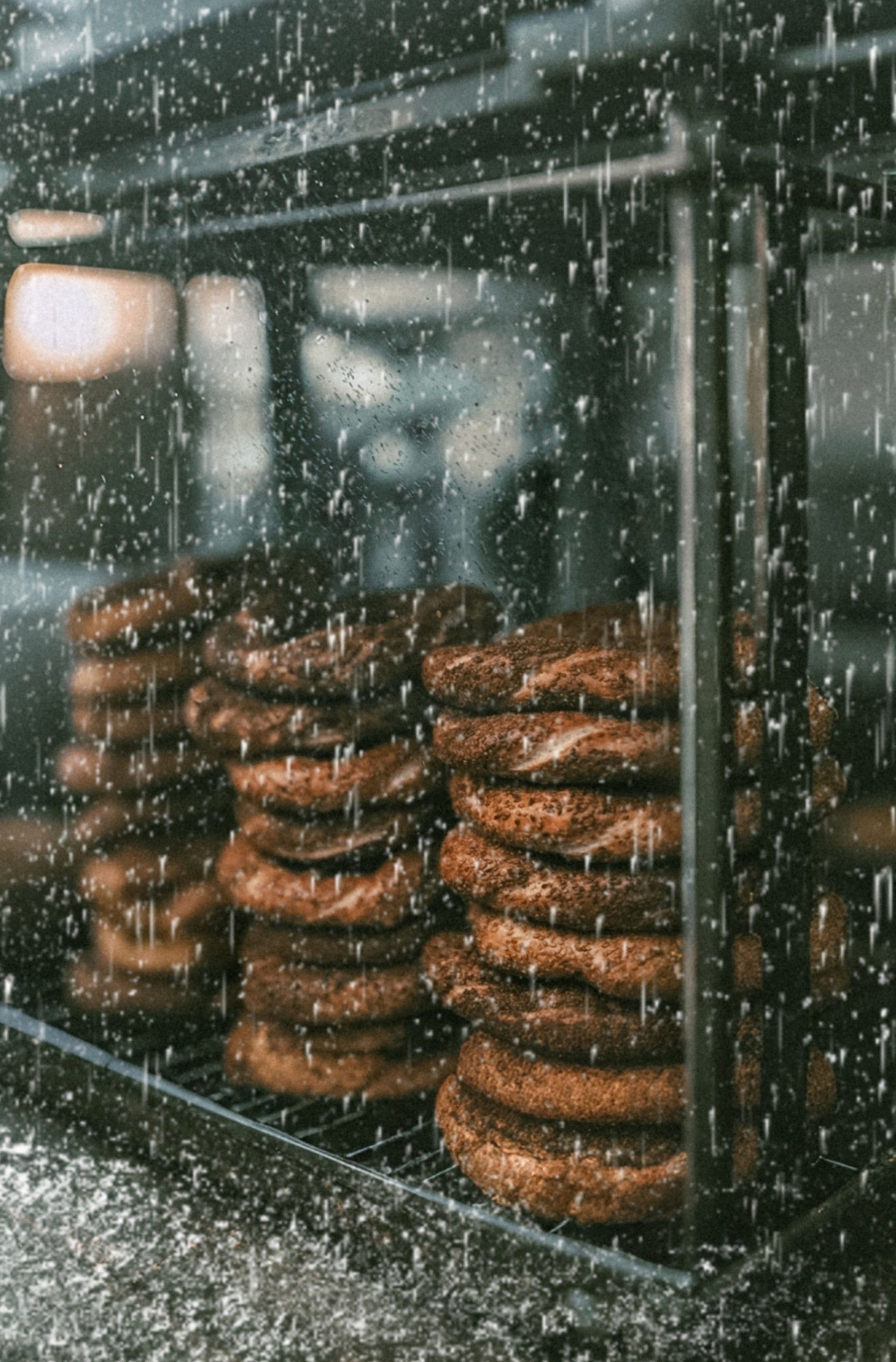 Fresh Bagels Behind a Rainy Glass Display · Free Stock Photo