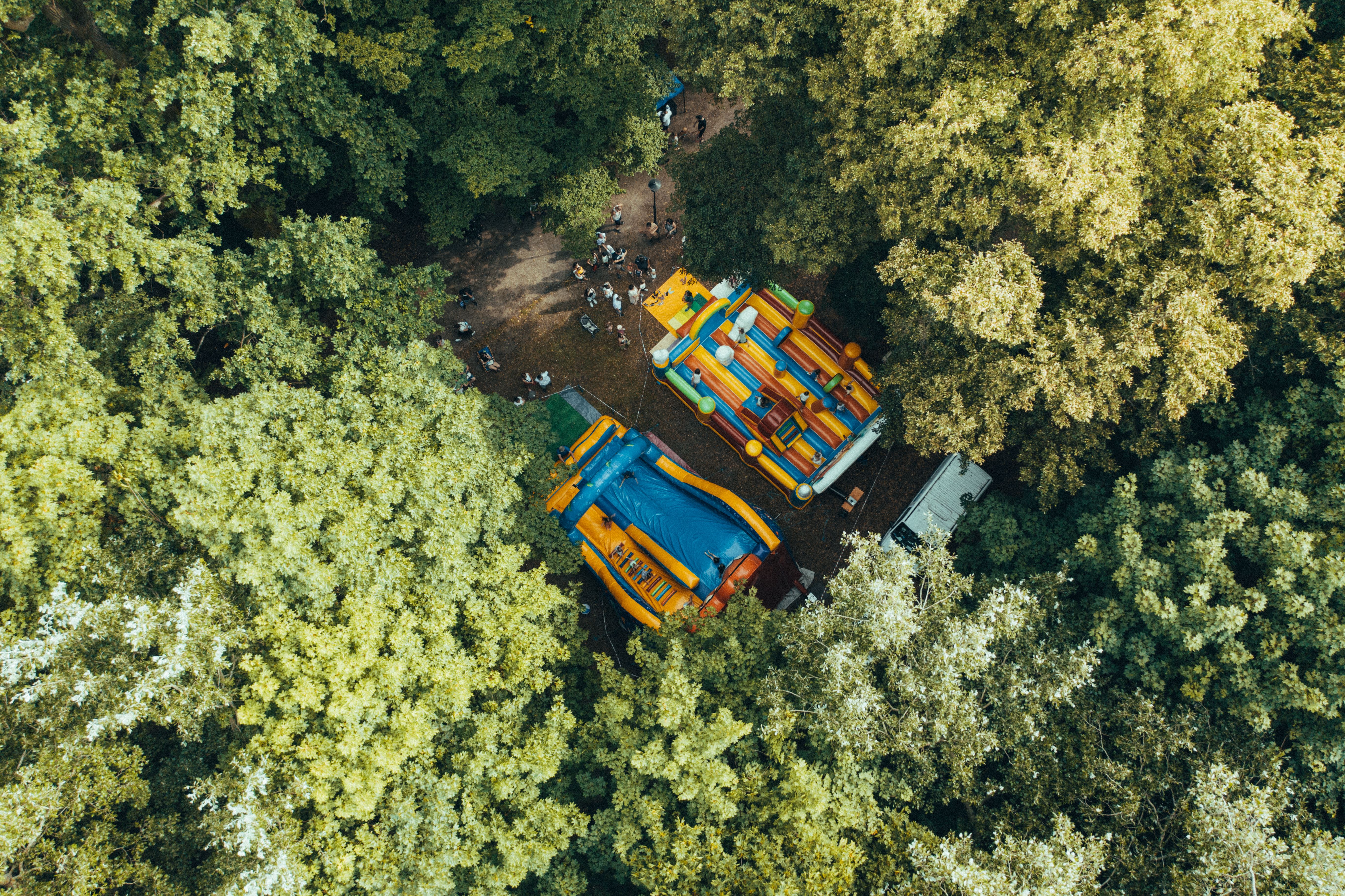 Aerial View of Colorful Inflatable Structures in Forest · Free Stock Photo