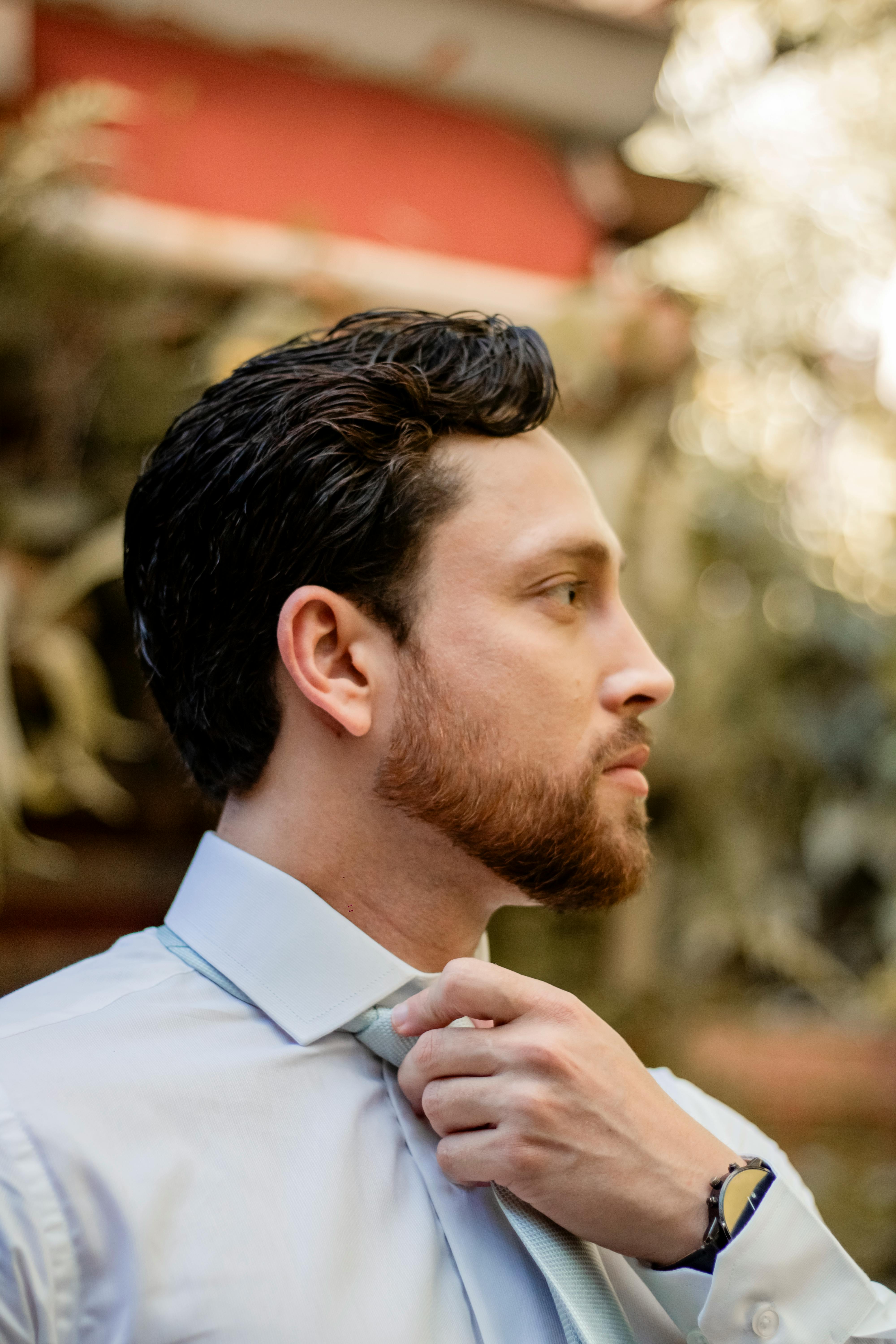 Thoughtful Young Man Adjusting Tie Outdoors · Free Stock Photo
