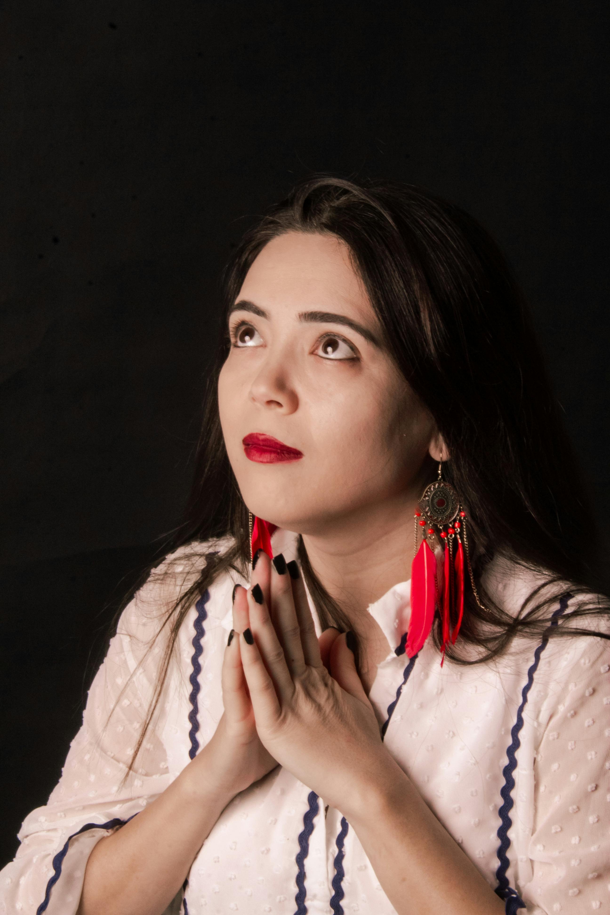 Pensive woman praying with clasped hands · Free Stock Photo