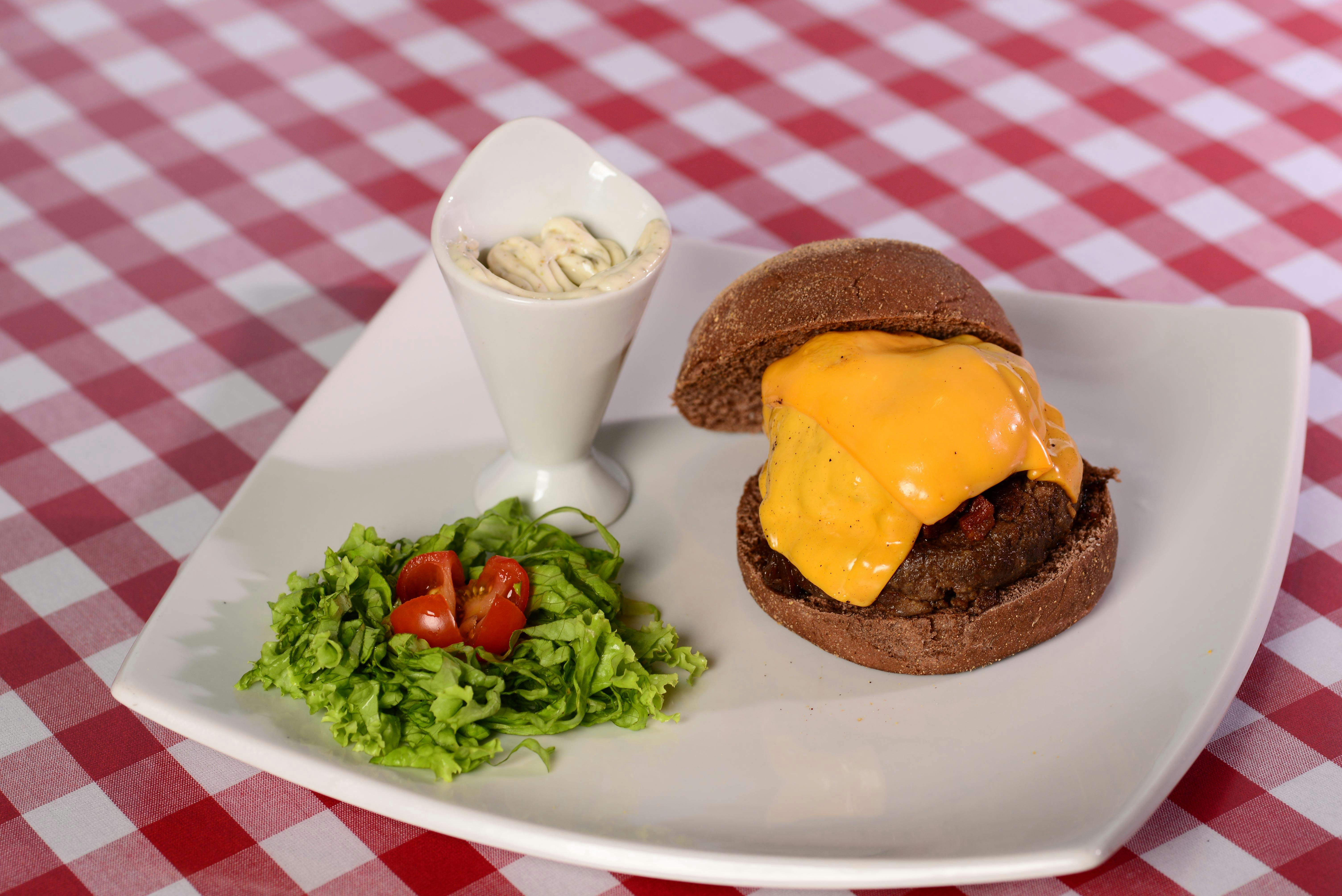 Gourmet Cheeseburger with Accompaniment on Checkered Table · Free Stock ...