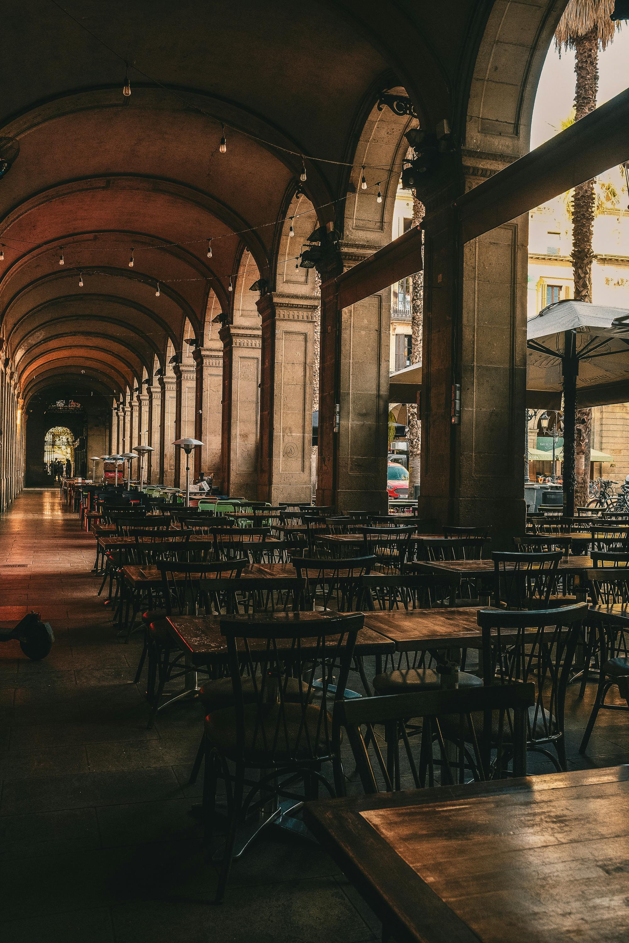 Elegant Arched Arcade with Outdoor Café Tables · Free Stock Photo