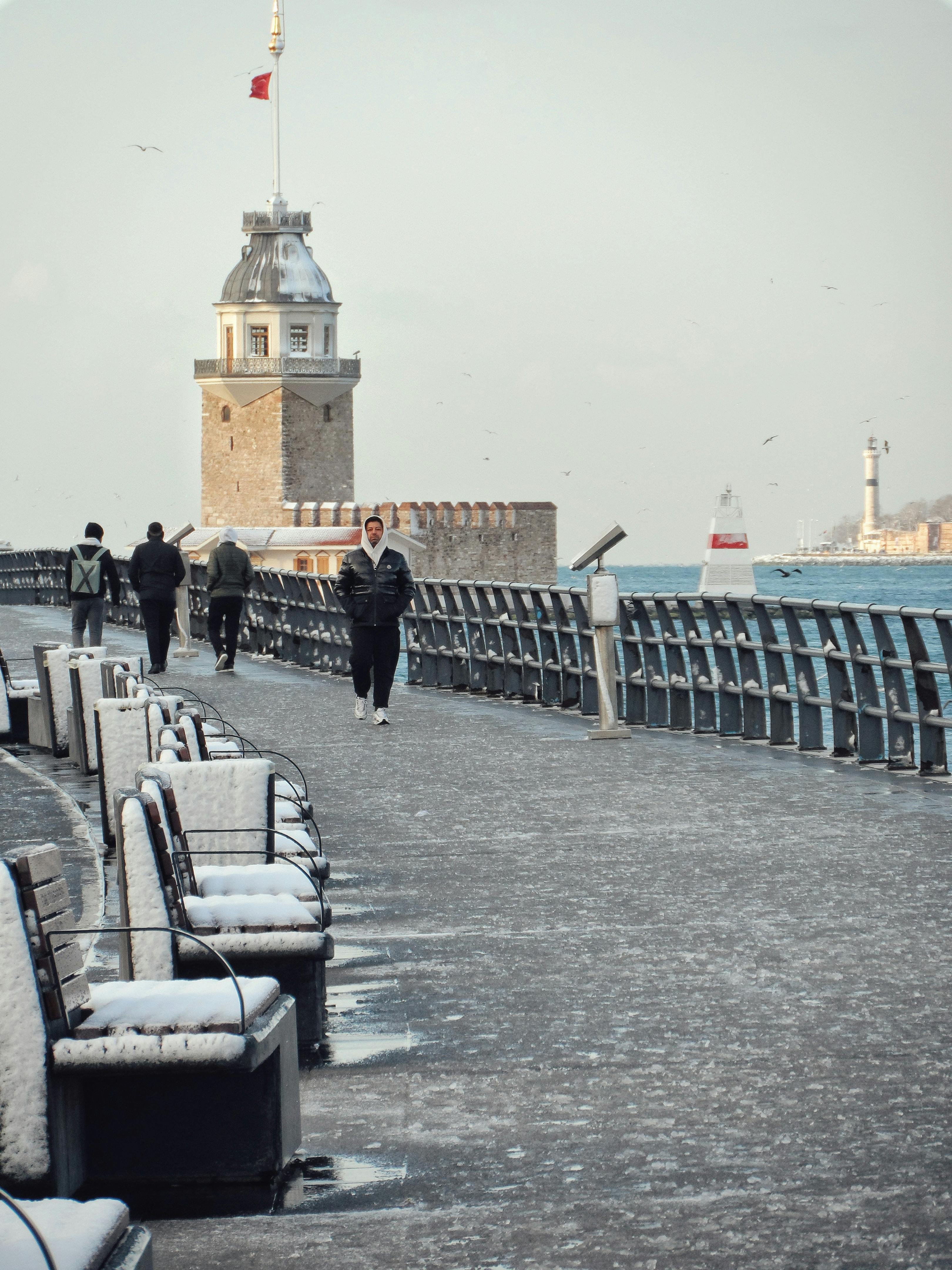 Snowy Harbor Walk with Historic Tower · Free Stock Photo