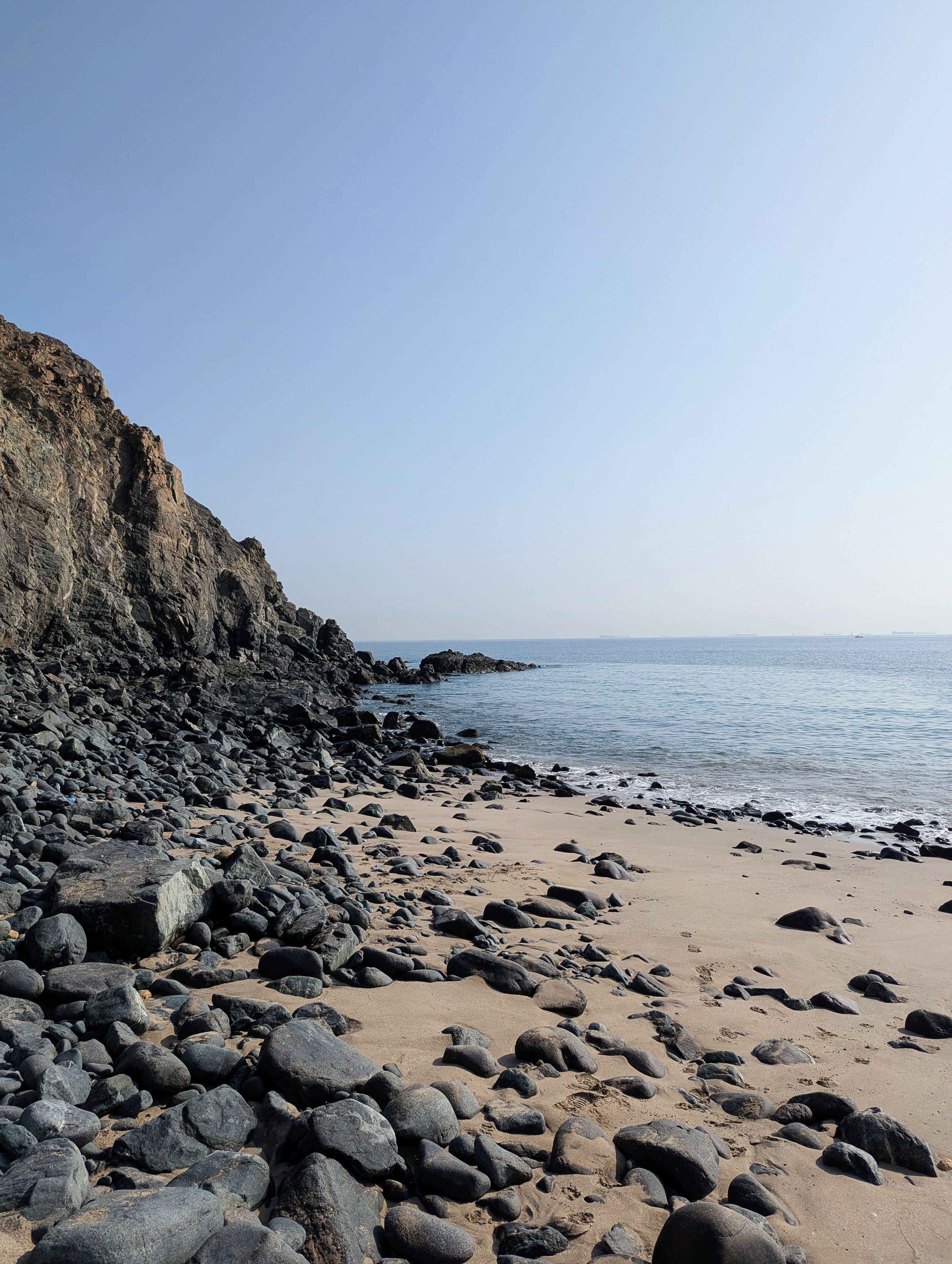 Rocky Beach Shoreline with Mountain Backdrop · Free Stock Photo