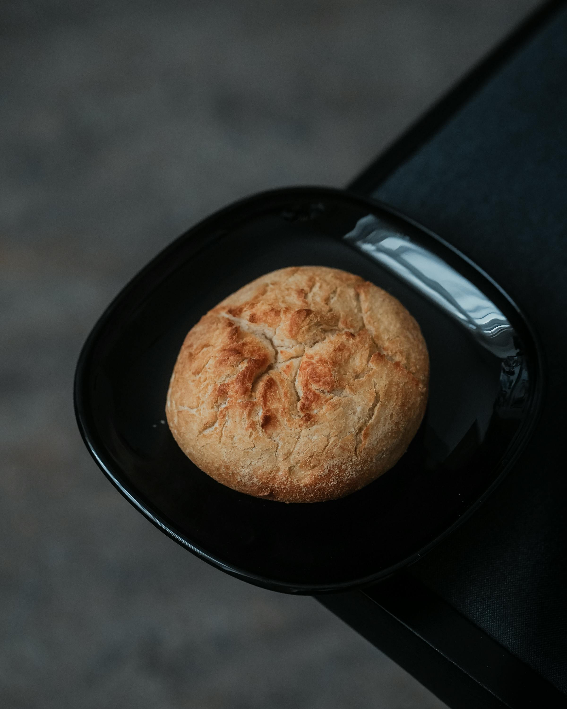 Rustic Bread Roll on Black Plate · Free Stock Photo