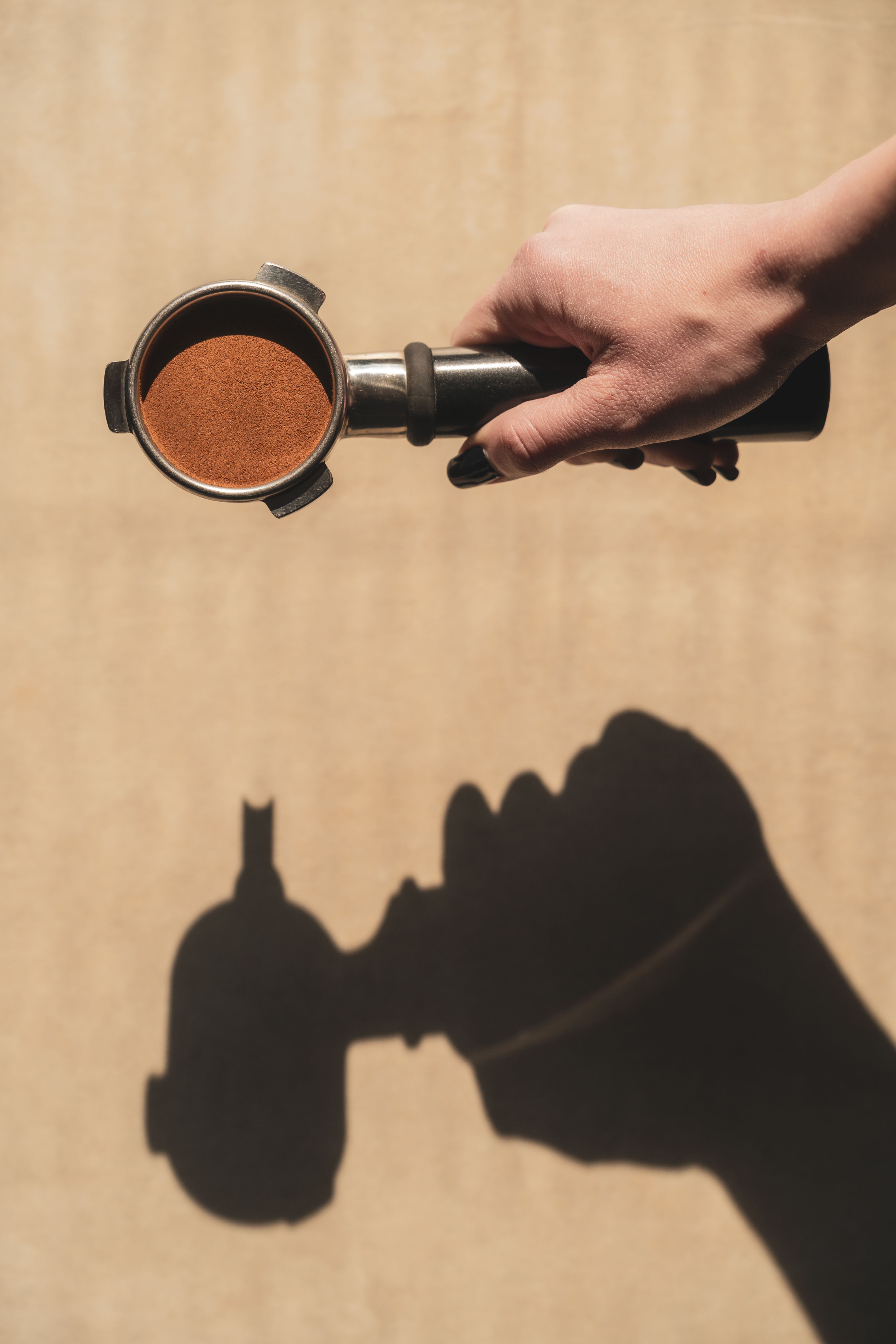 Barista holding coffee portafilter casting shadow · Free Stock Photo