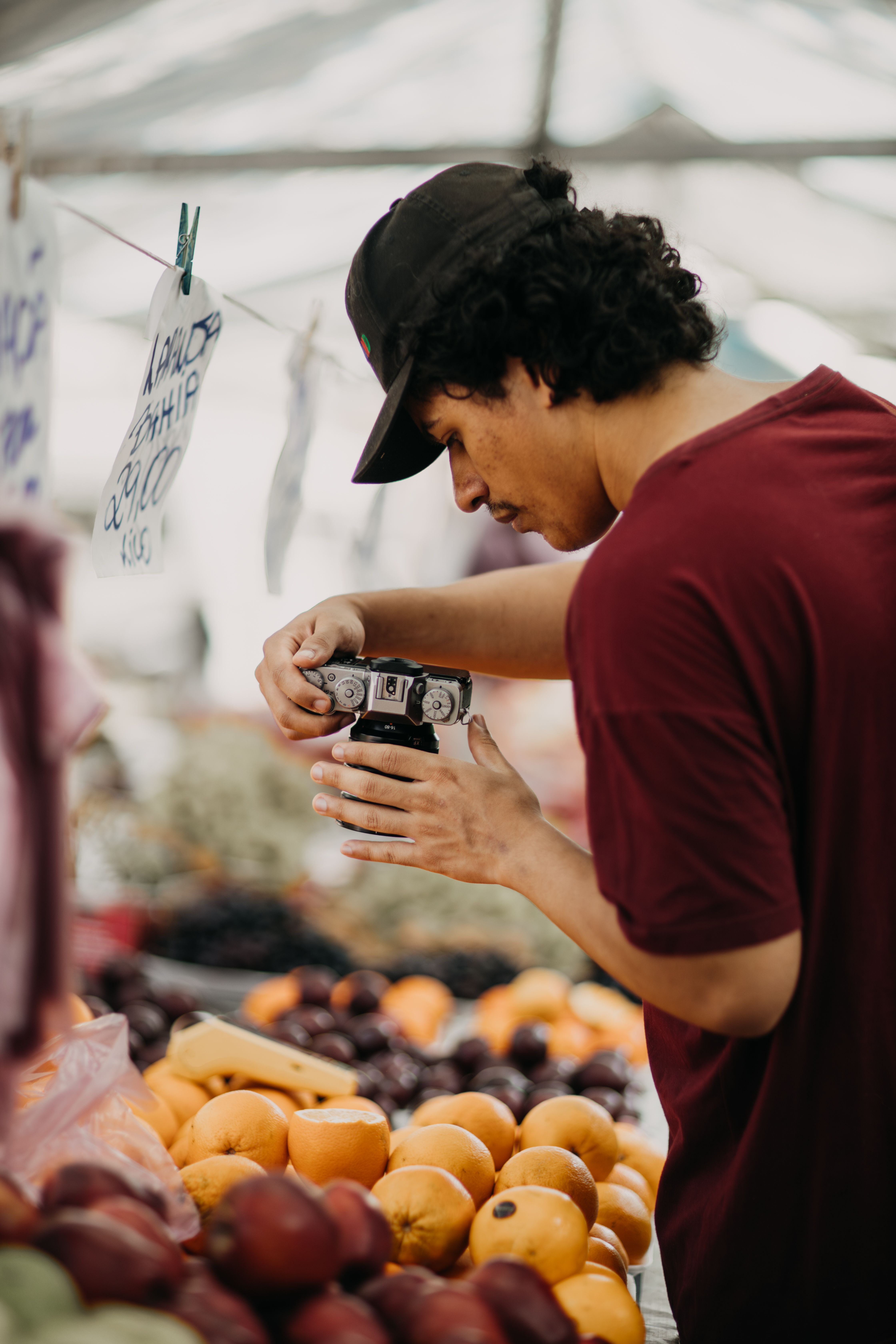 Young Man Photographing Fresh Produce at Market · Free Stock Photo