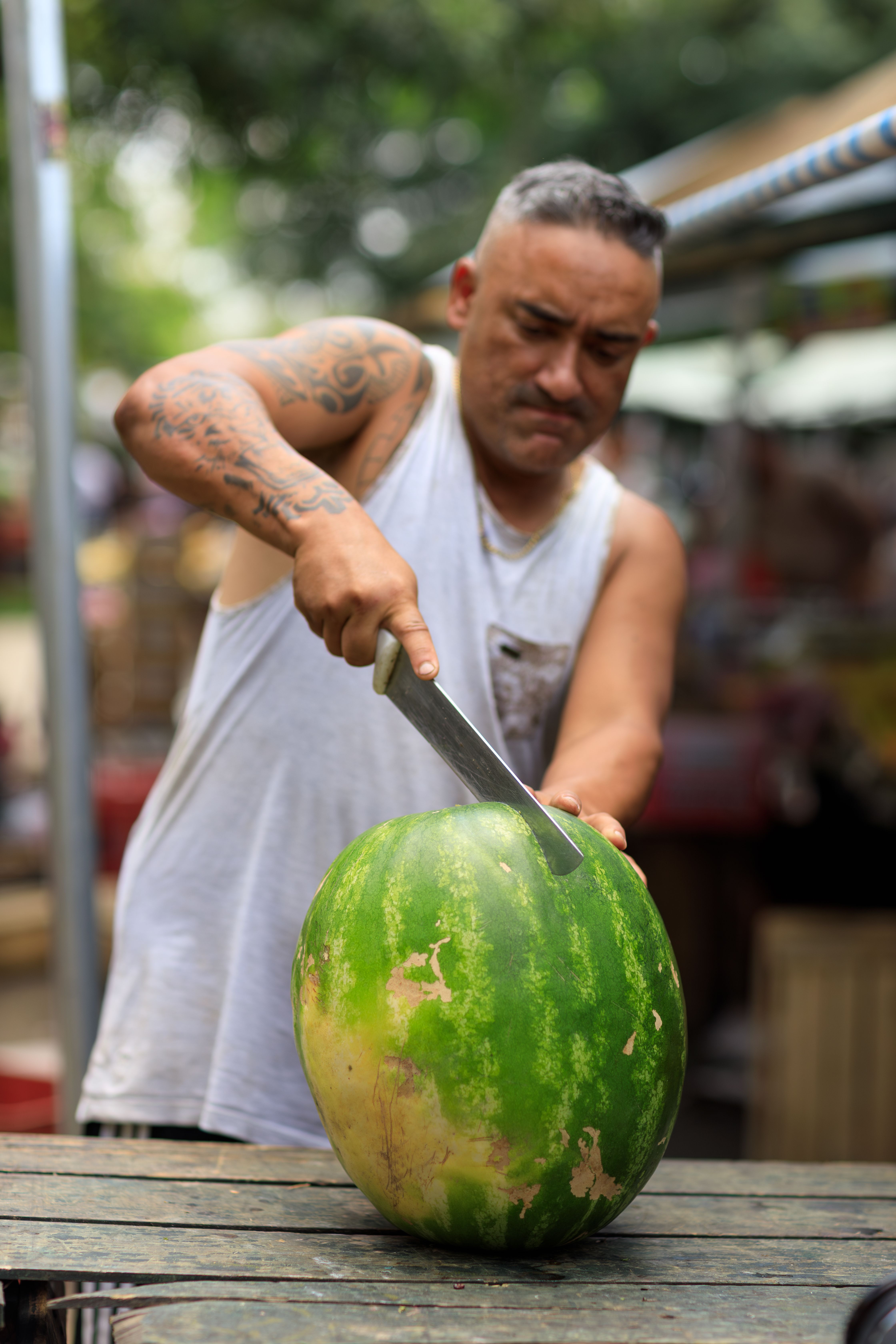 Man Slicing Watermelon at Outdoor Market · Free Stock Photo