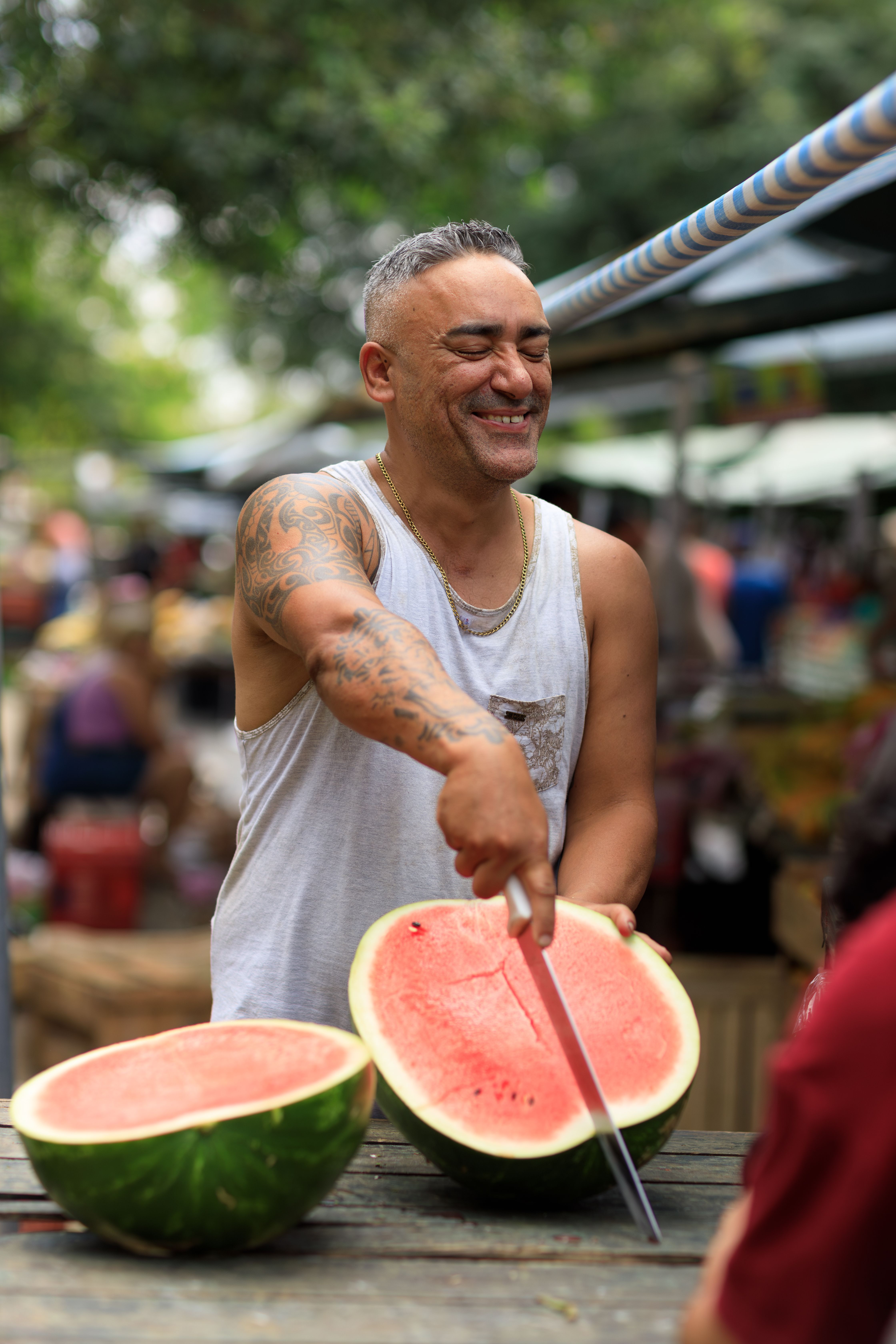 Smiling Vendor Cutting Fresh Watermelon at Market · Free Stock Photo