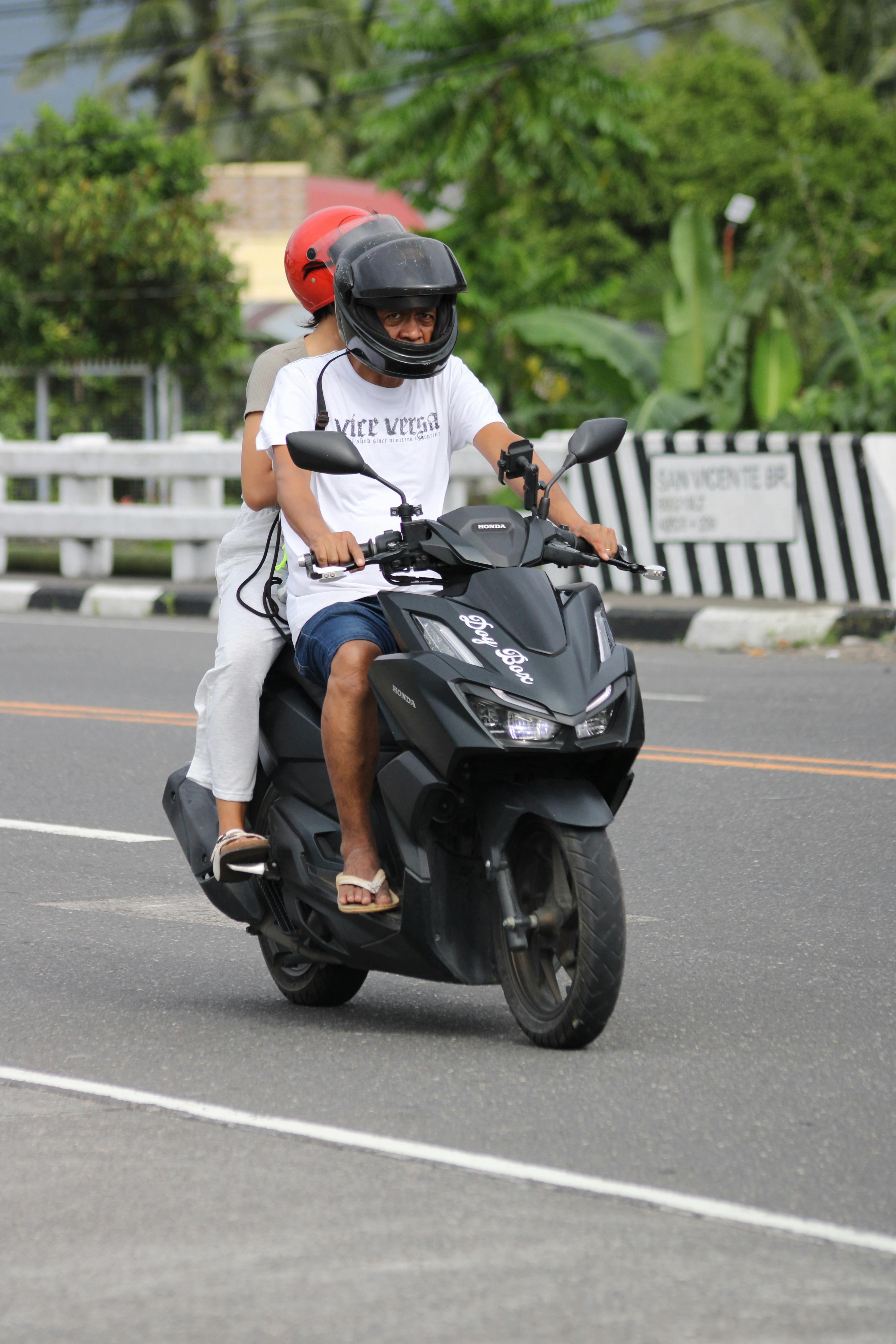 Two adults riding a scooter on a sunny day · Free Stock Photo