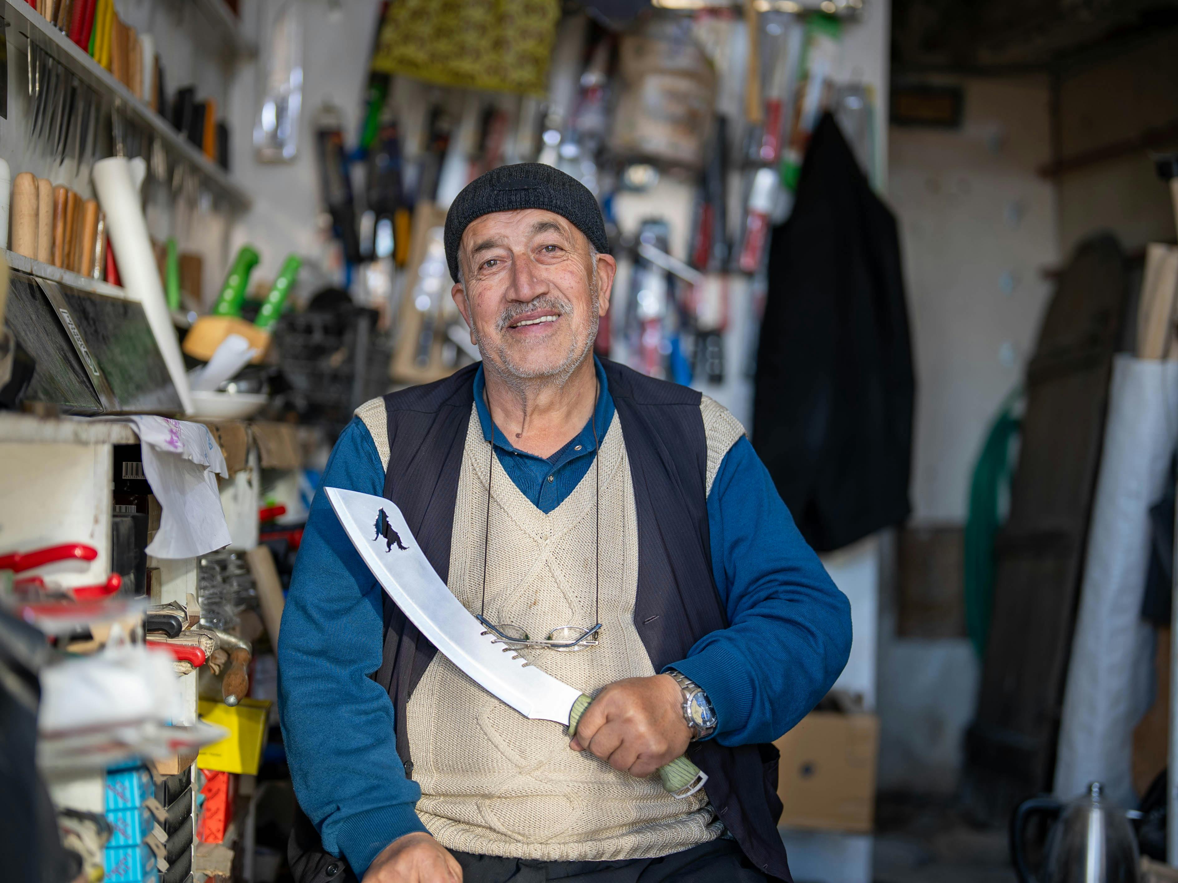 Smiling Tradesman with Large Knife in Workshop · Free Stock Photo