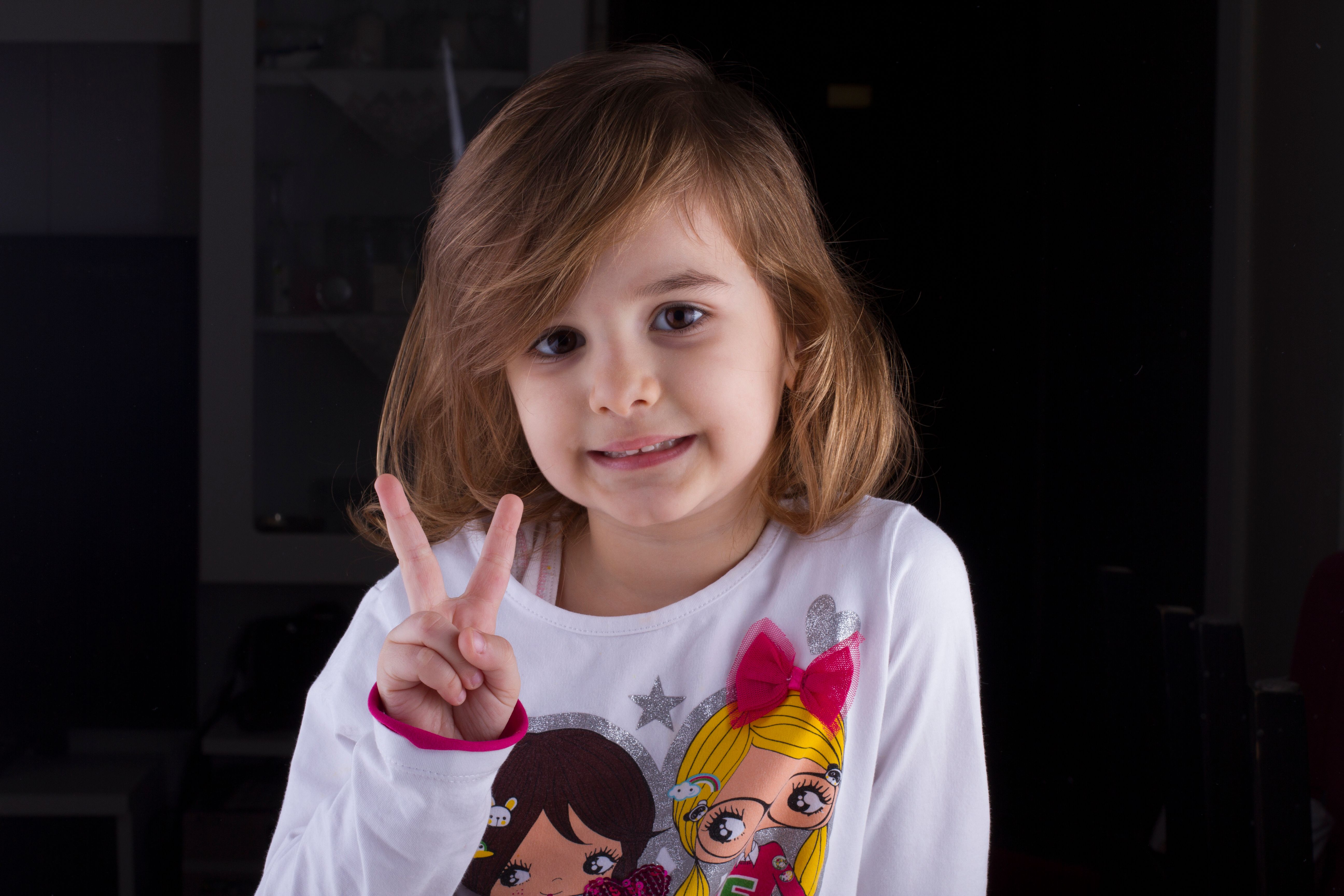 Cheerful Child Making Peace Sign Indoors · Free Stock Photo