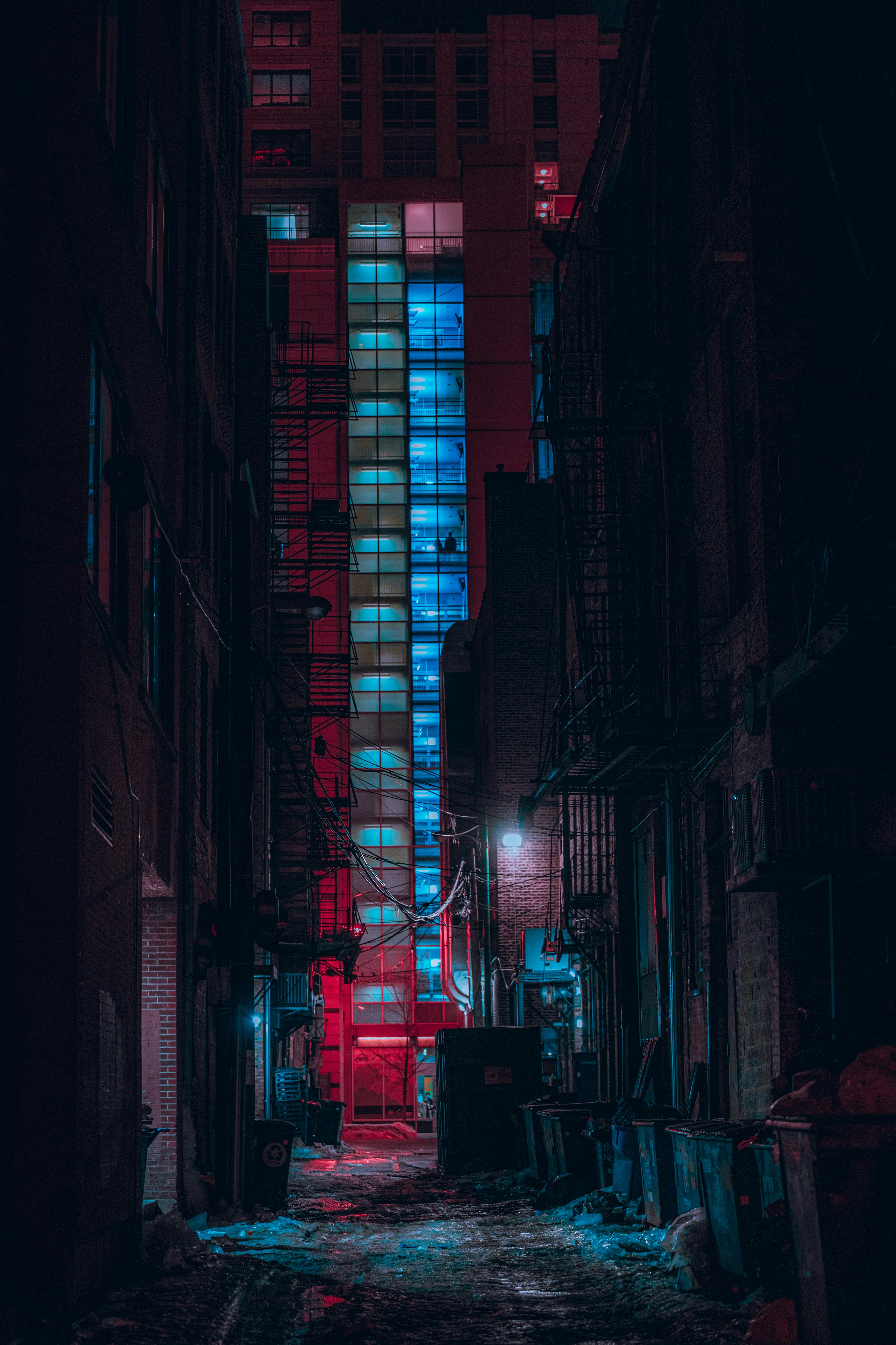 Neon Lit Urban Alley with Skyscraper View · Free Stock Photo