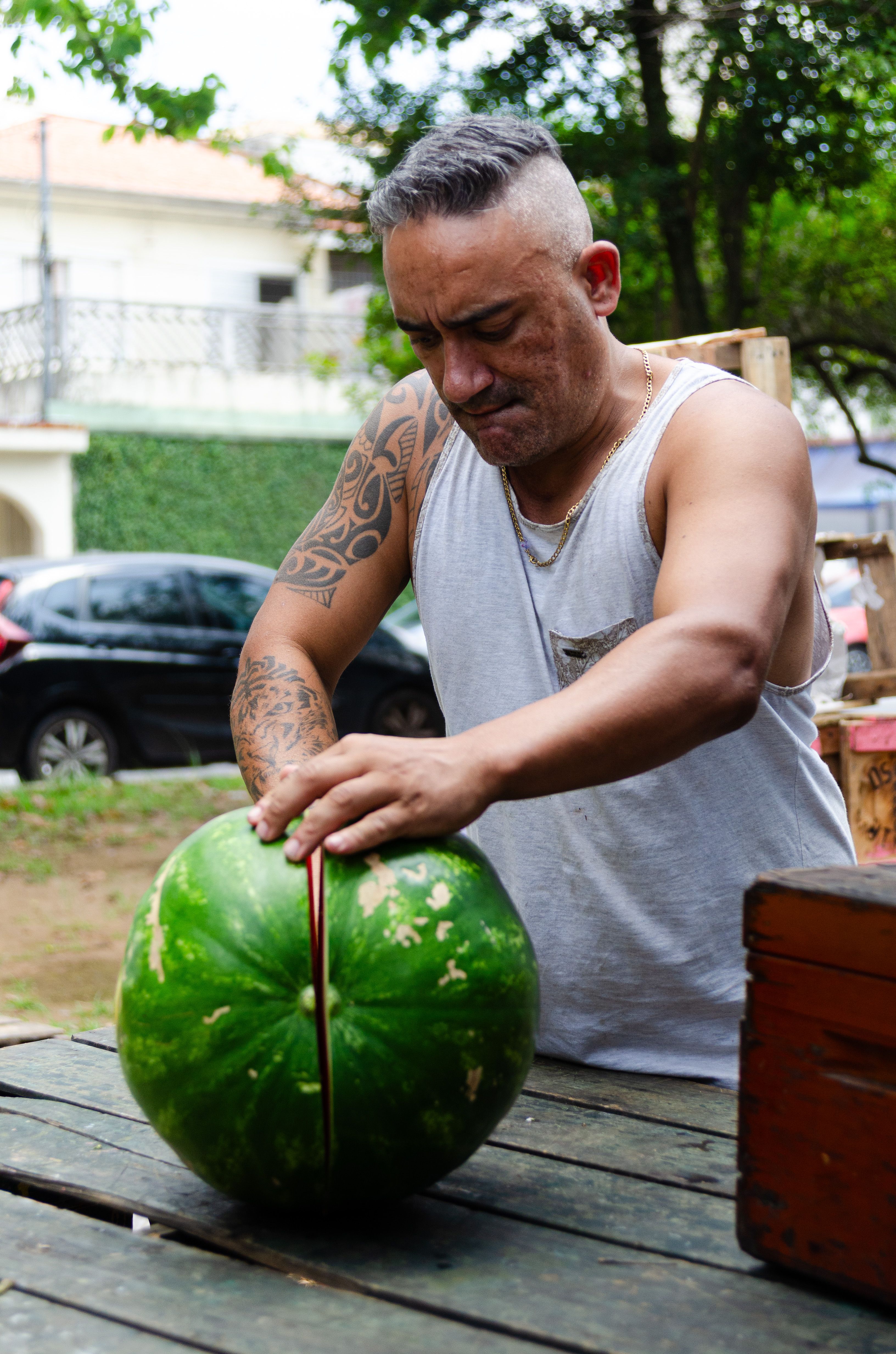 Man slicing watermelon outdoors at market · Free Stock Photo