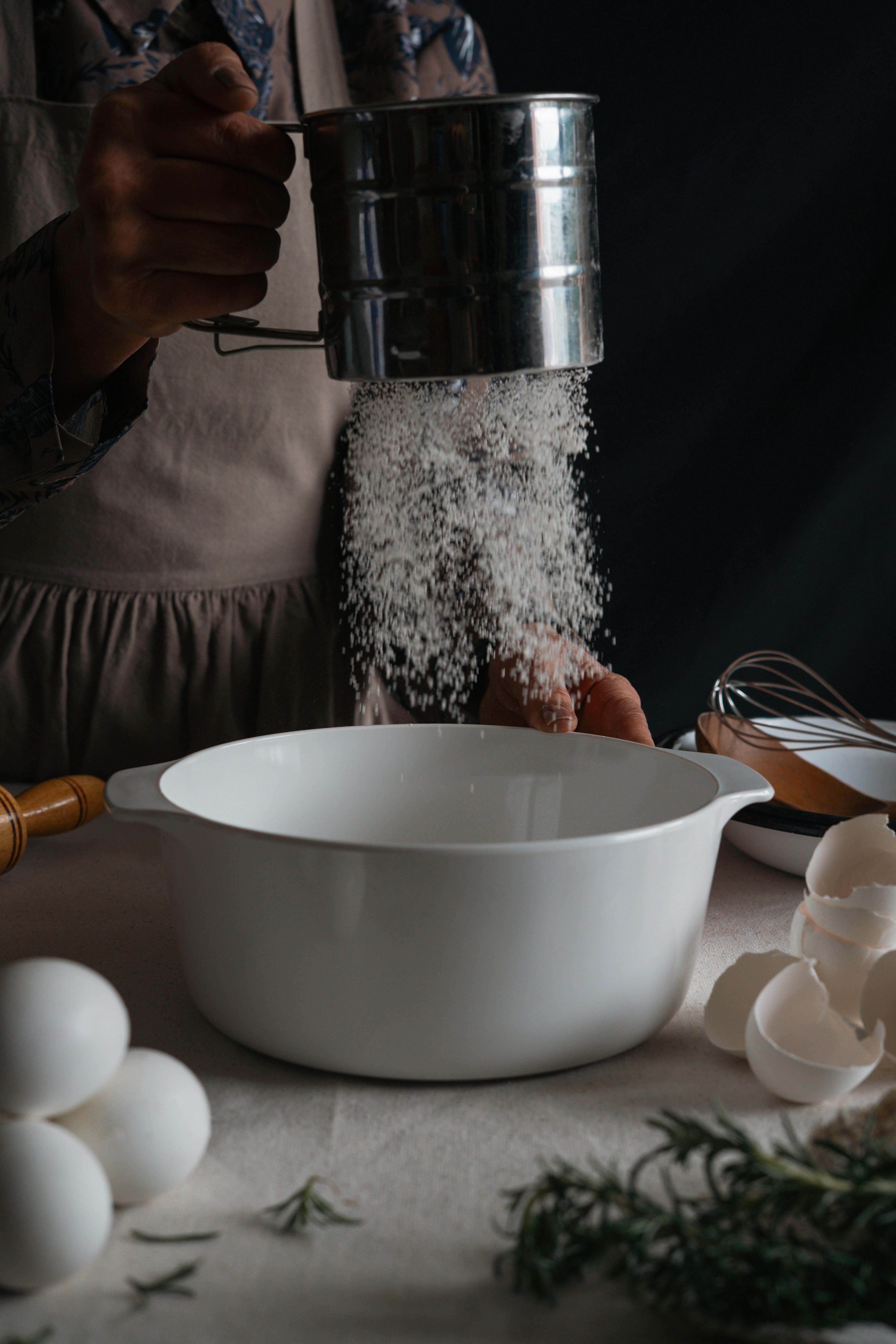 Person Sifting Flour into a White Bowl · Free Stock Photo
