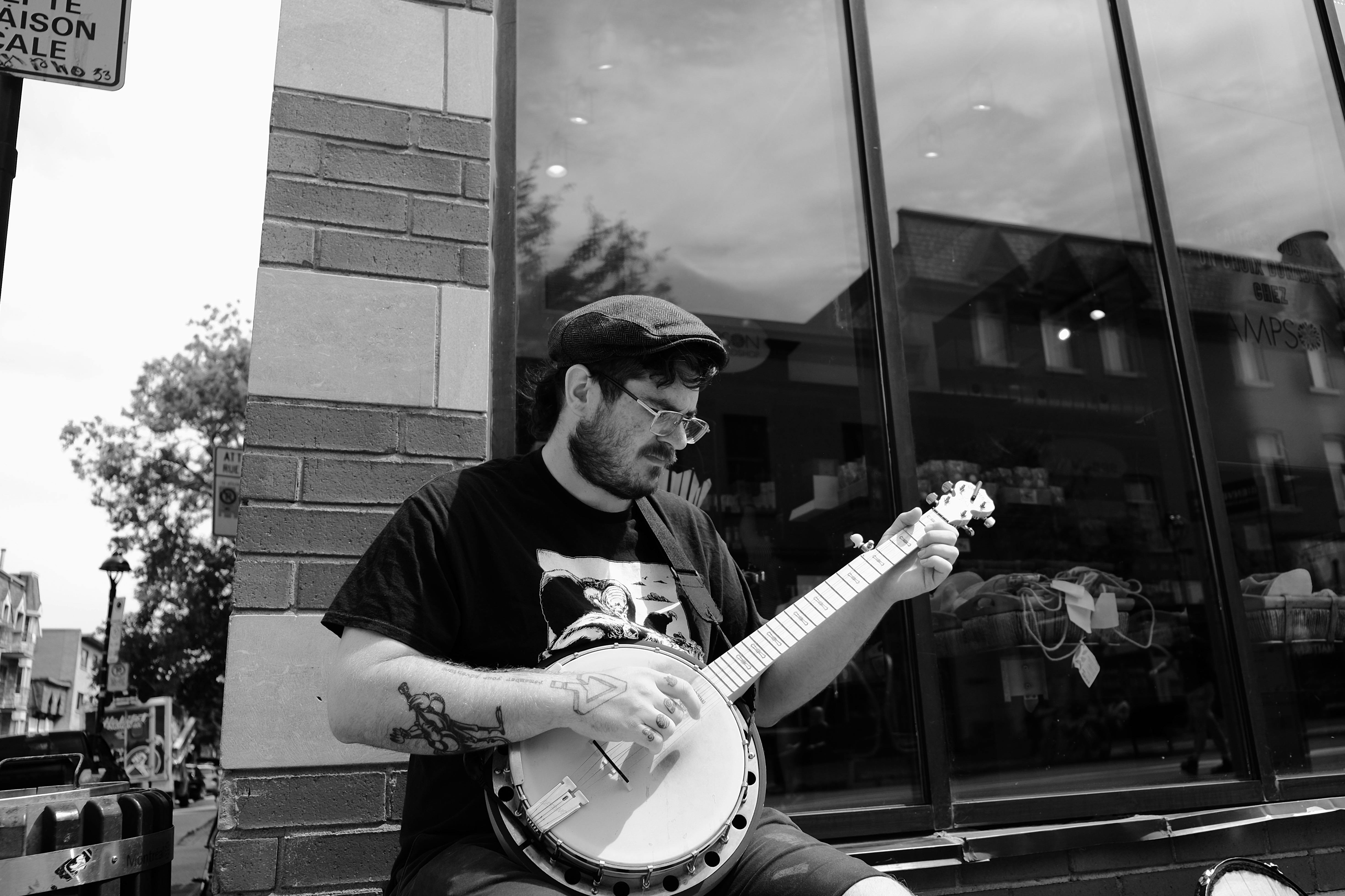 Street musician playing banjo outside urban cafe · Free Stock Photo