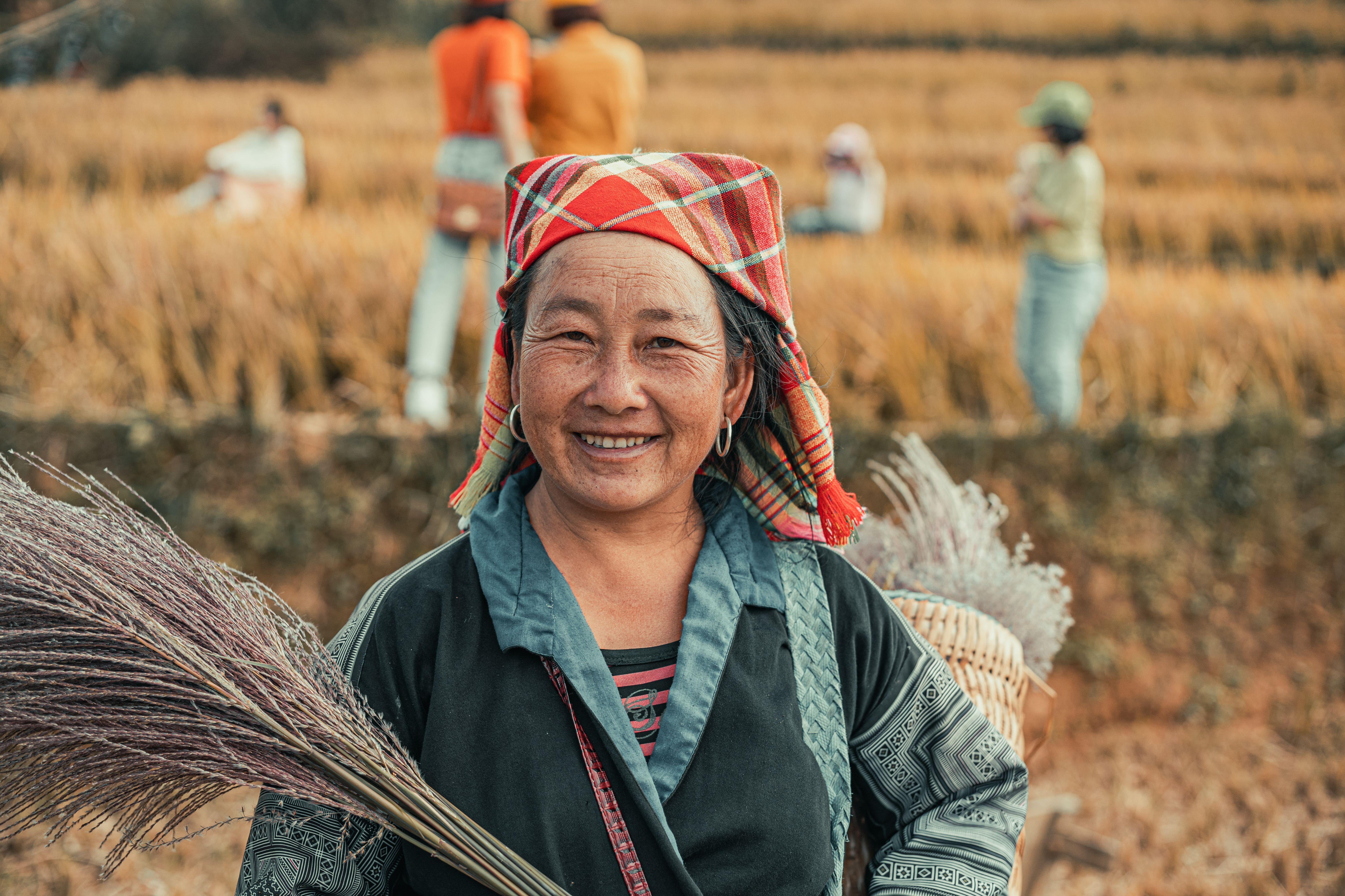 Smiling Woman in Traditional Attire in Harvest Field · Free Stock Photo