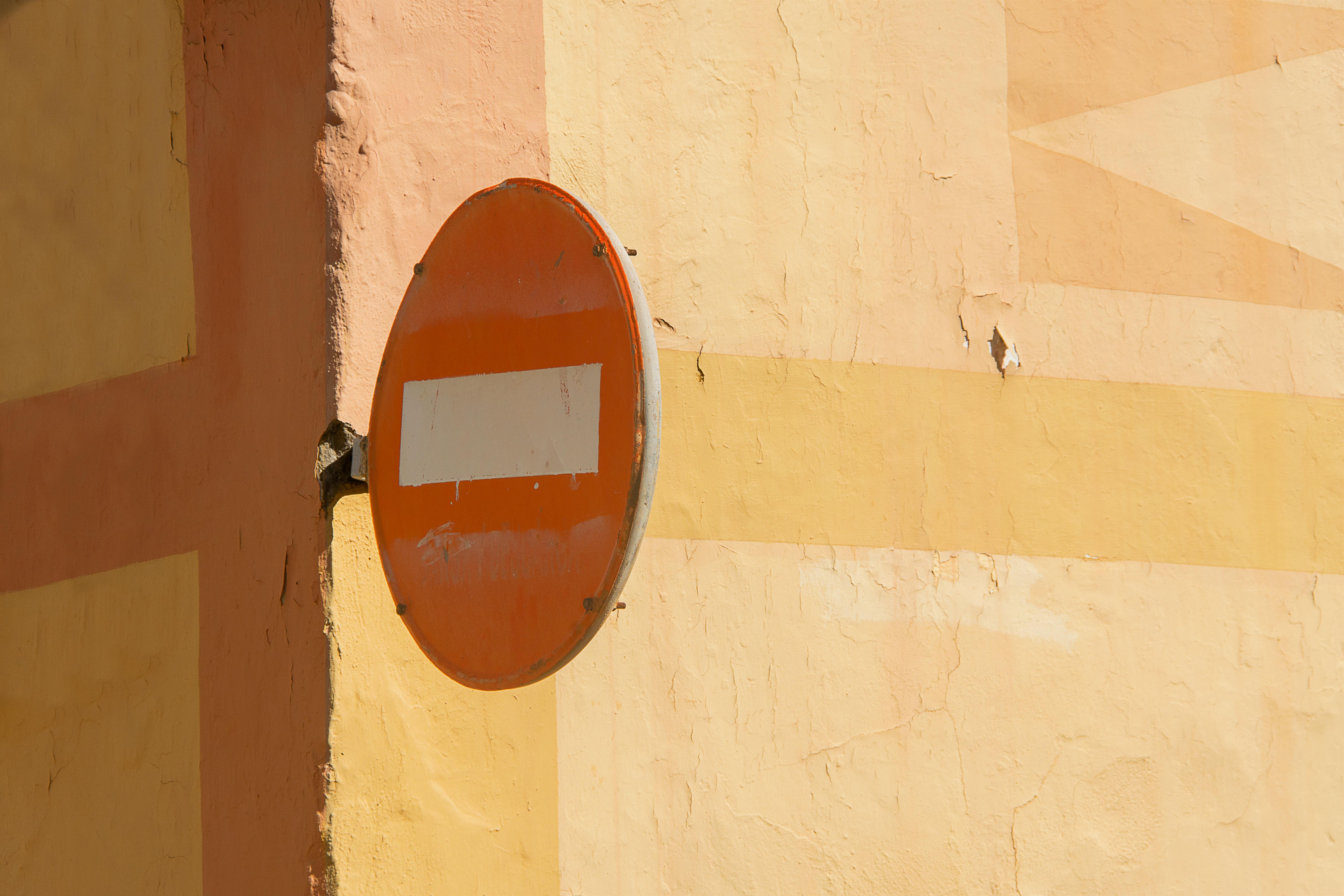 Weathered Traffic Sign on Sunlit Wall Corner · Free Stock Photo