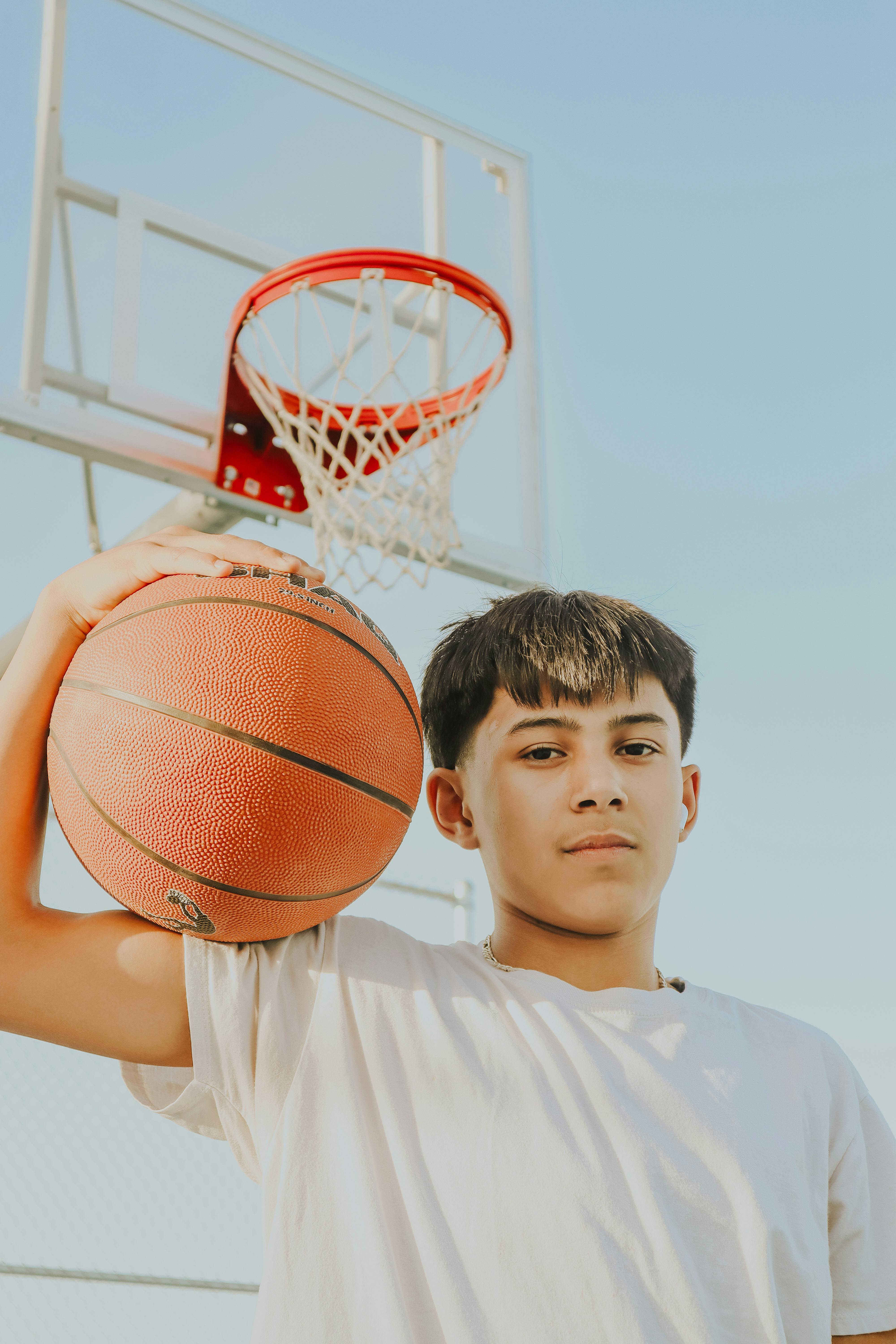 Teen Boy Holding Basketball on Outdoor Court · Free Stock Photo