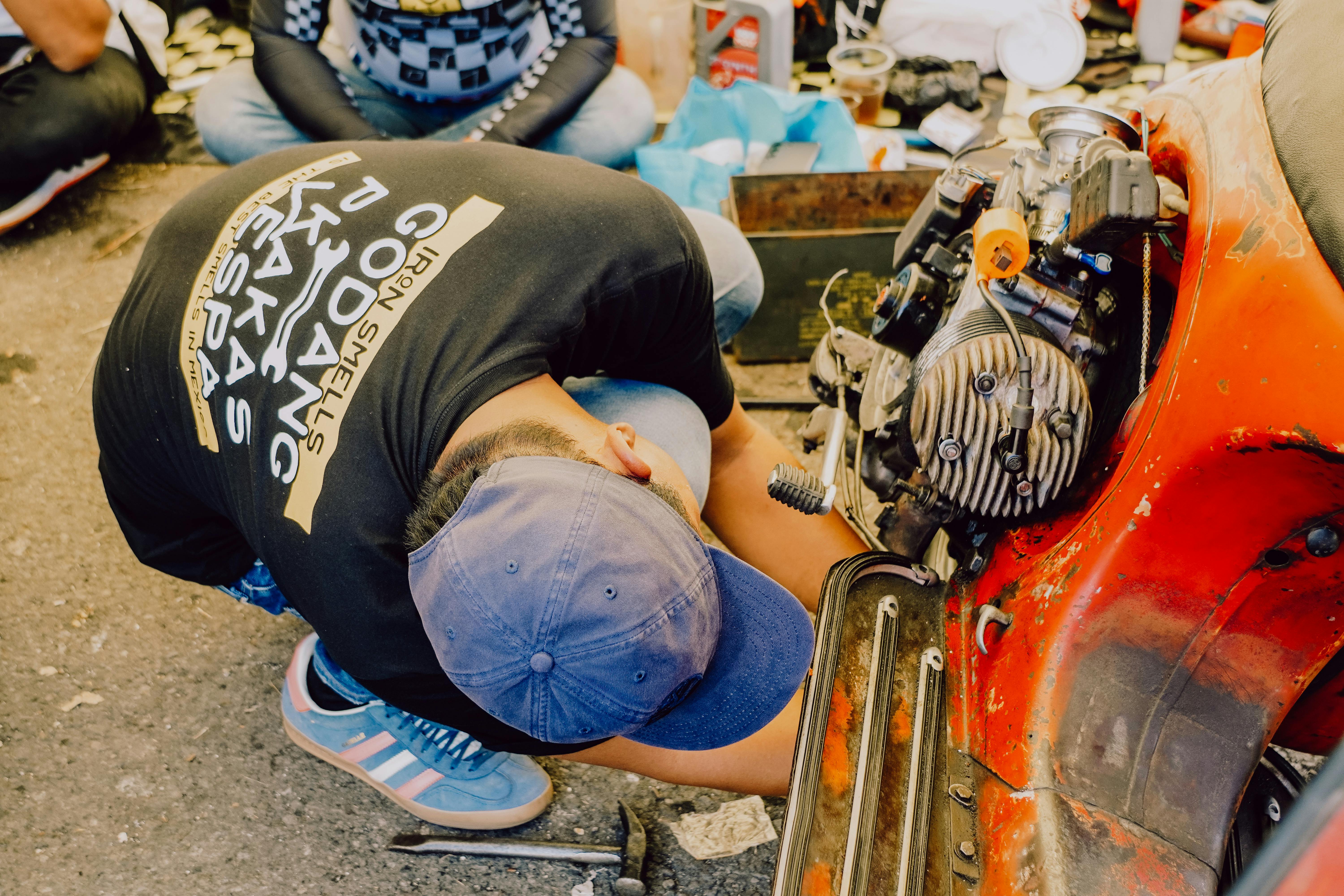 Man Repairing Motorcycle Engine Outdoors · Free Stock Photo