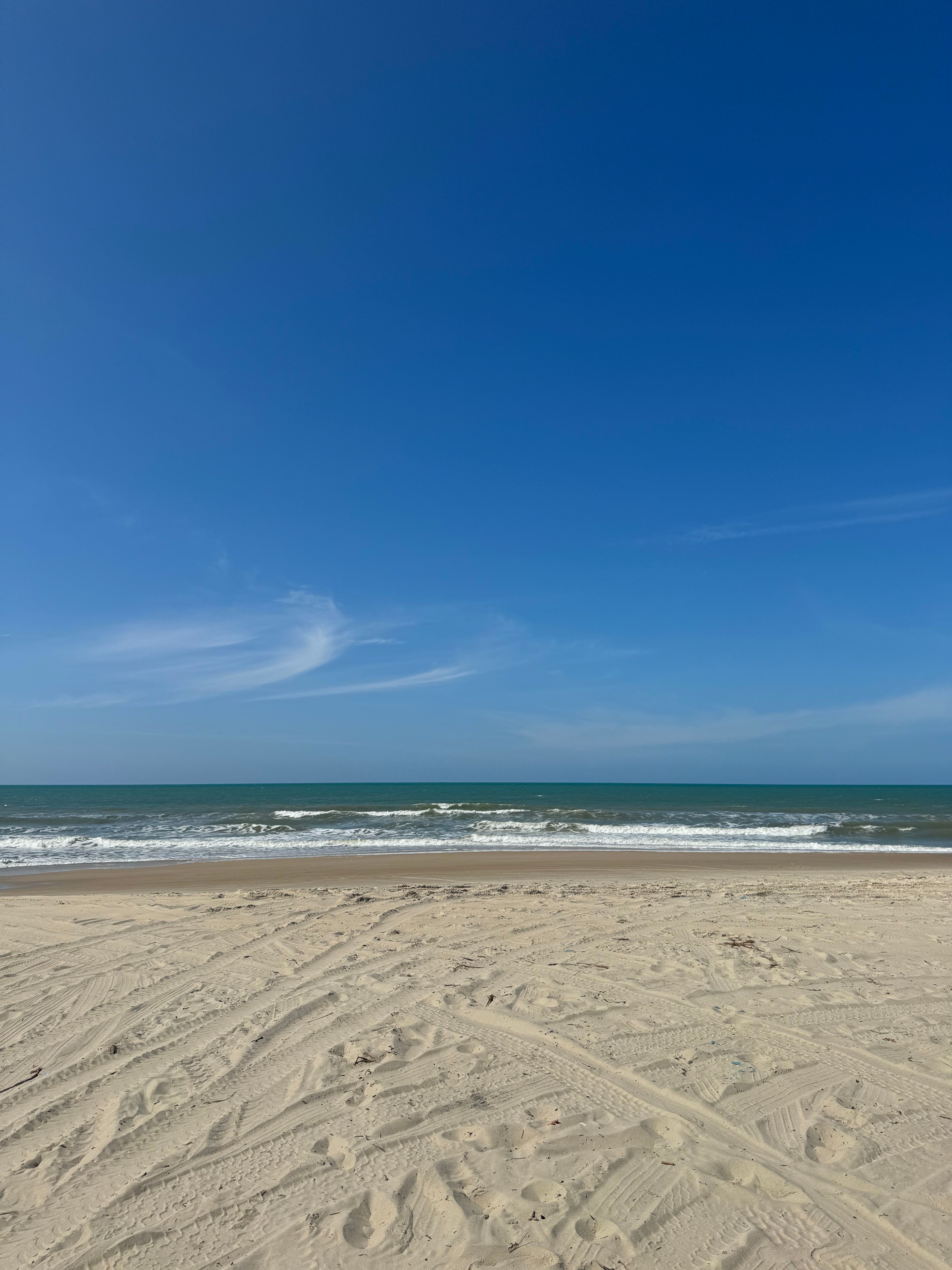 Serene Sandy Beach with Blue Sky and Ocean Waves · Free Stock Photo
