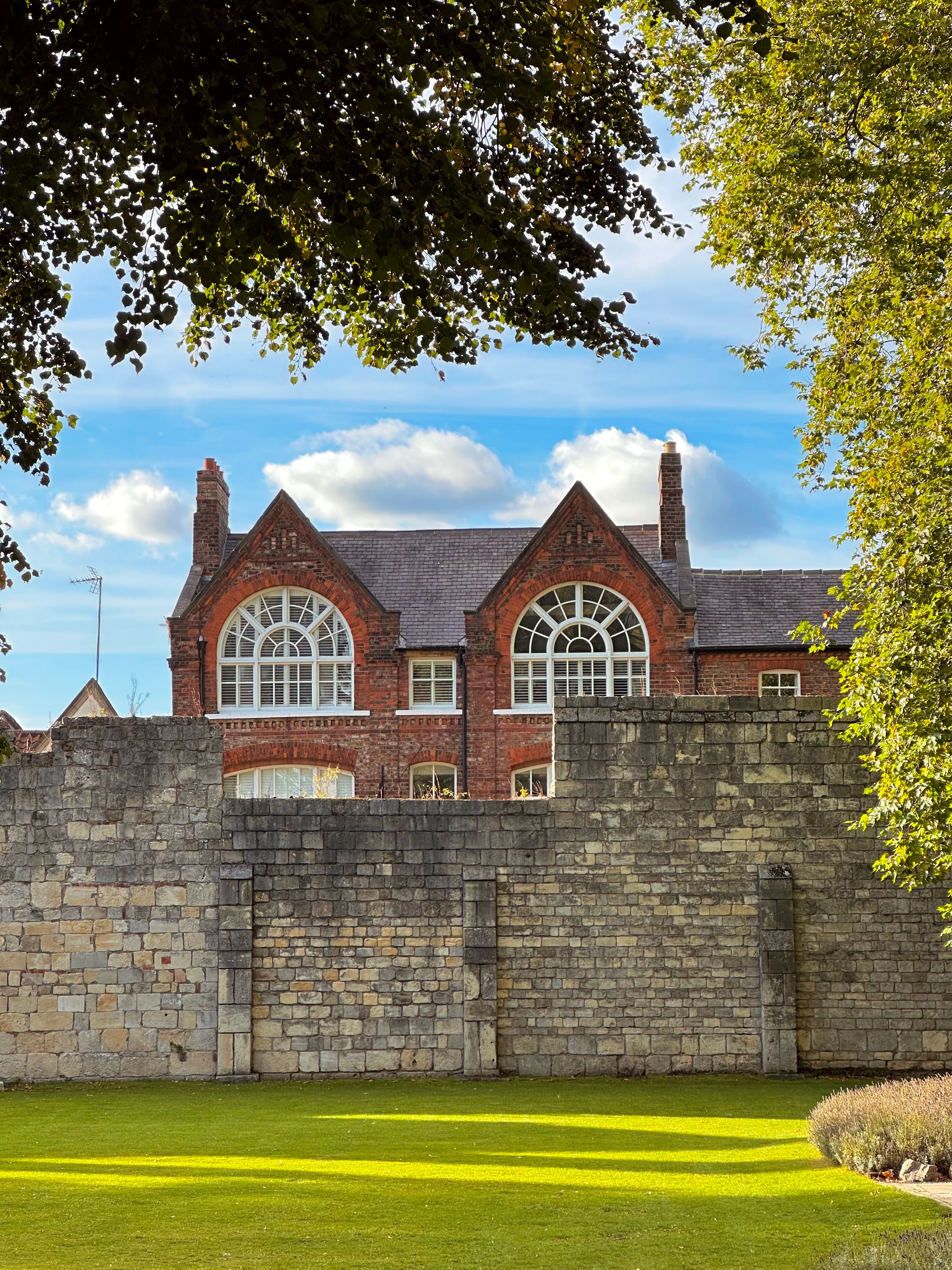 Historic Brick Building Behind Ancient Wall · Free Stock Photo